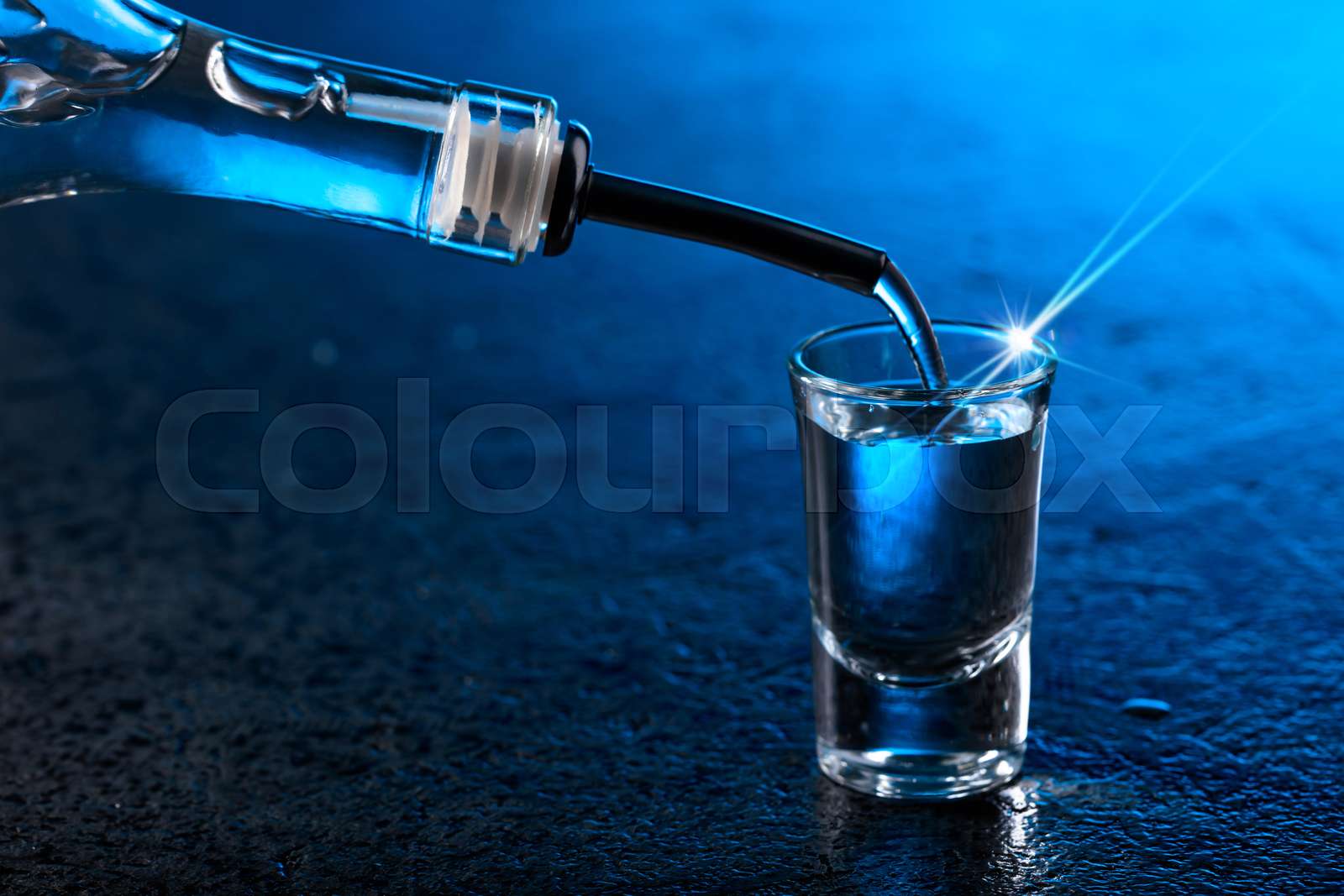 Vodka poured into a glass lit with blue backlight. | Stock image ...