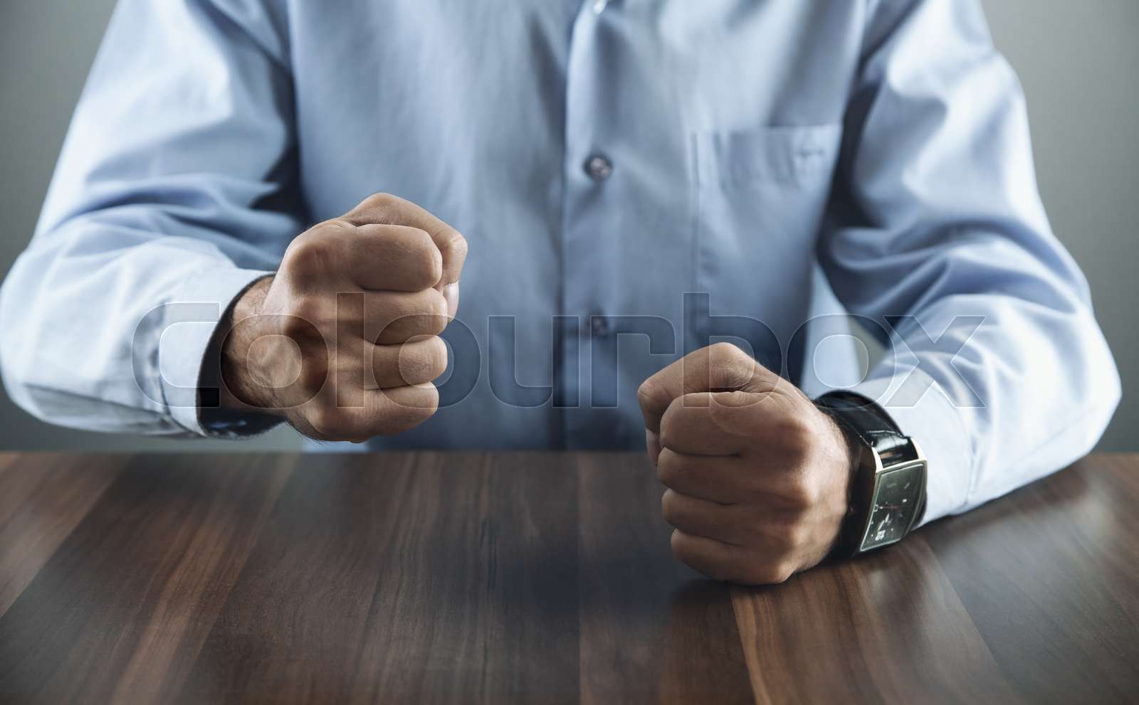 Angry businessman fists in the table. | Stock image | Colourbox