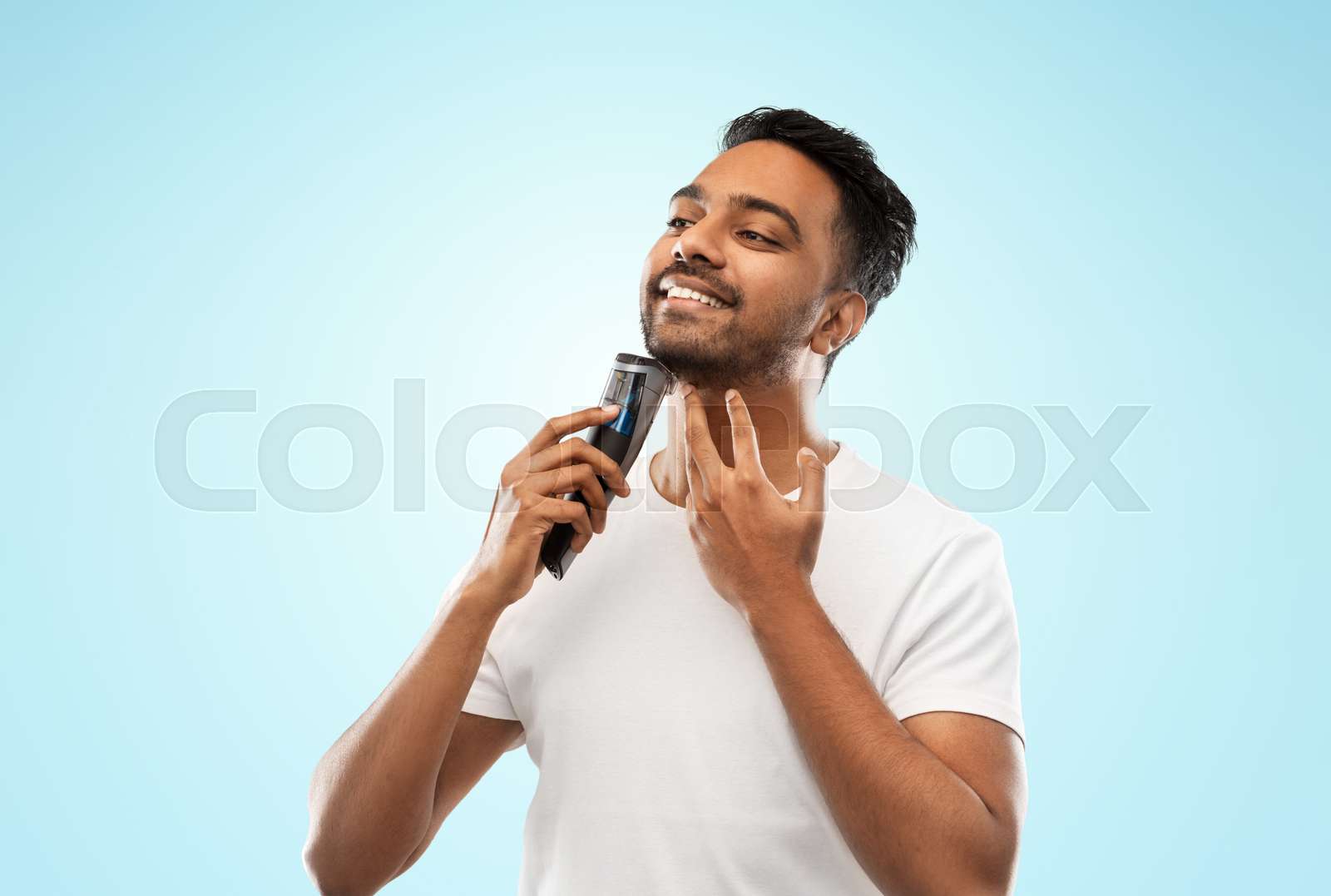 smiling indian man shaving beard with trimmer | Stock image | Colourbox