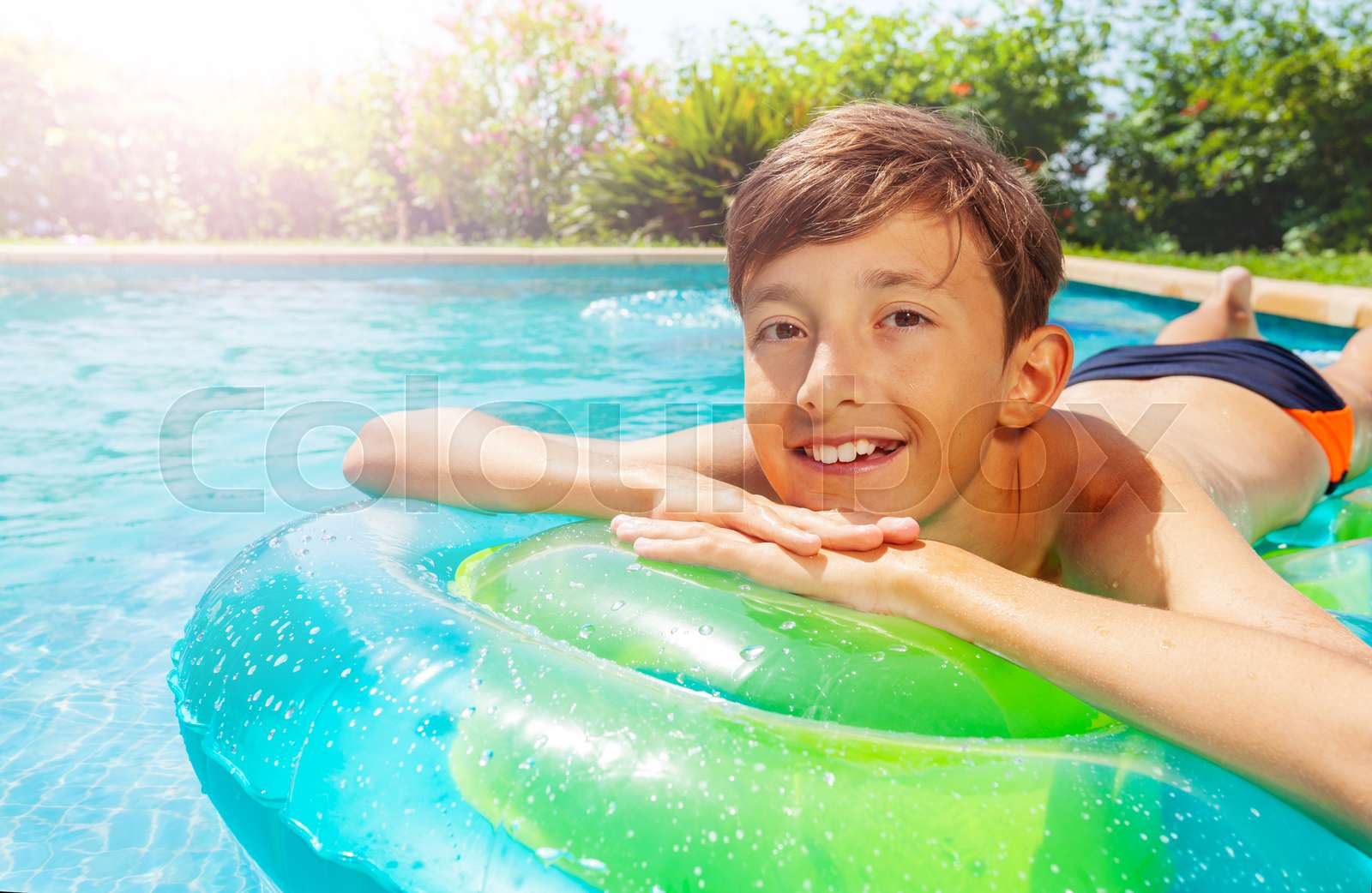 Happy teen boy sunbathing on inflatable mattress | Stock image | Colourbox