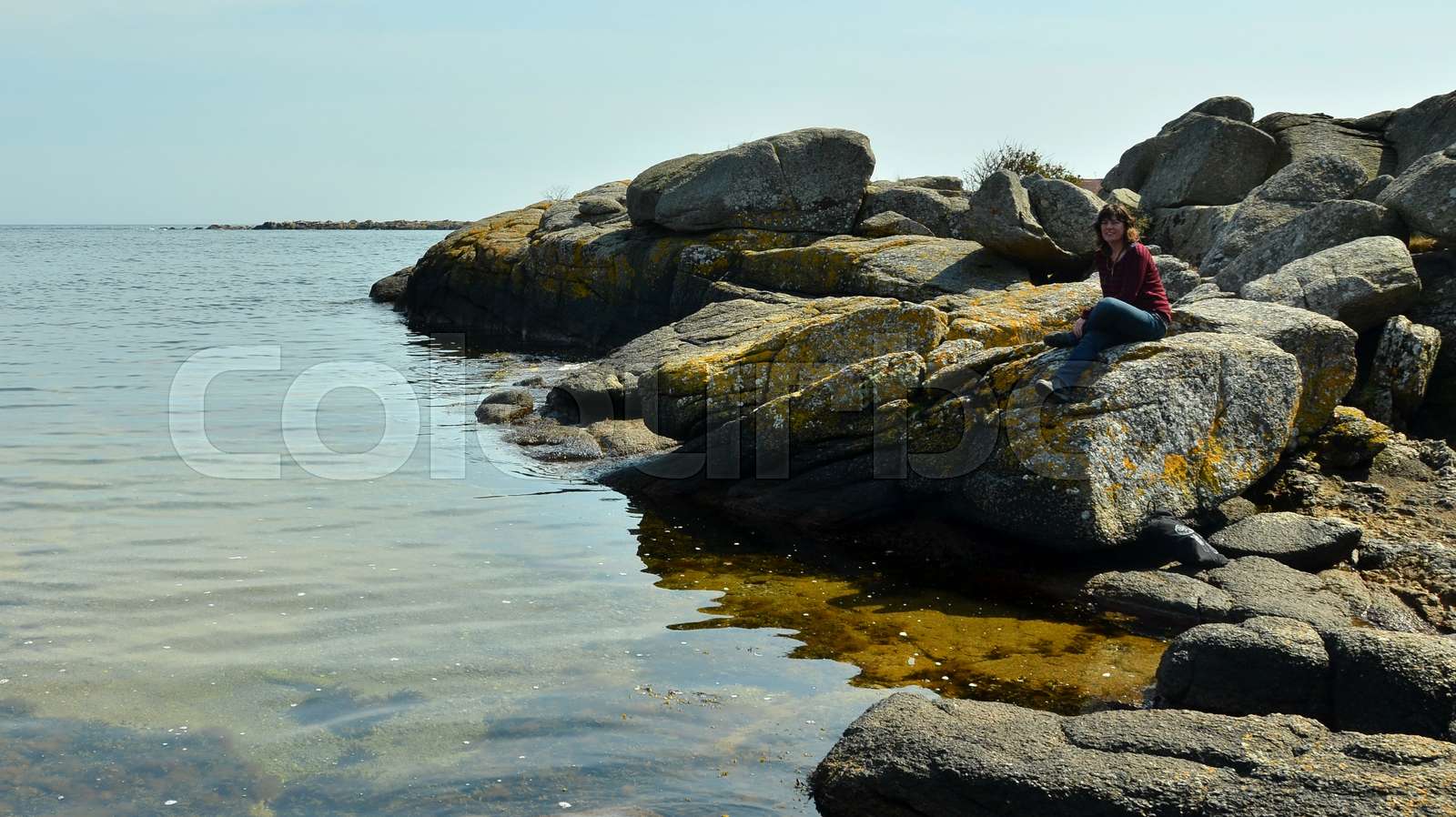 En Kvinde sidder på nogen Klipper ved Svaneke på Bornholm | Stock foto ...