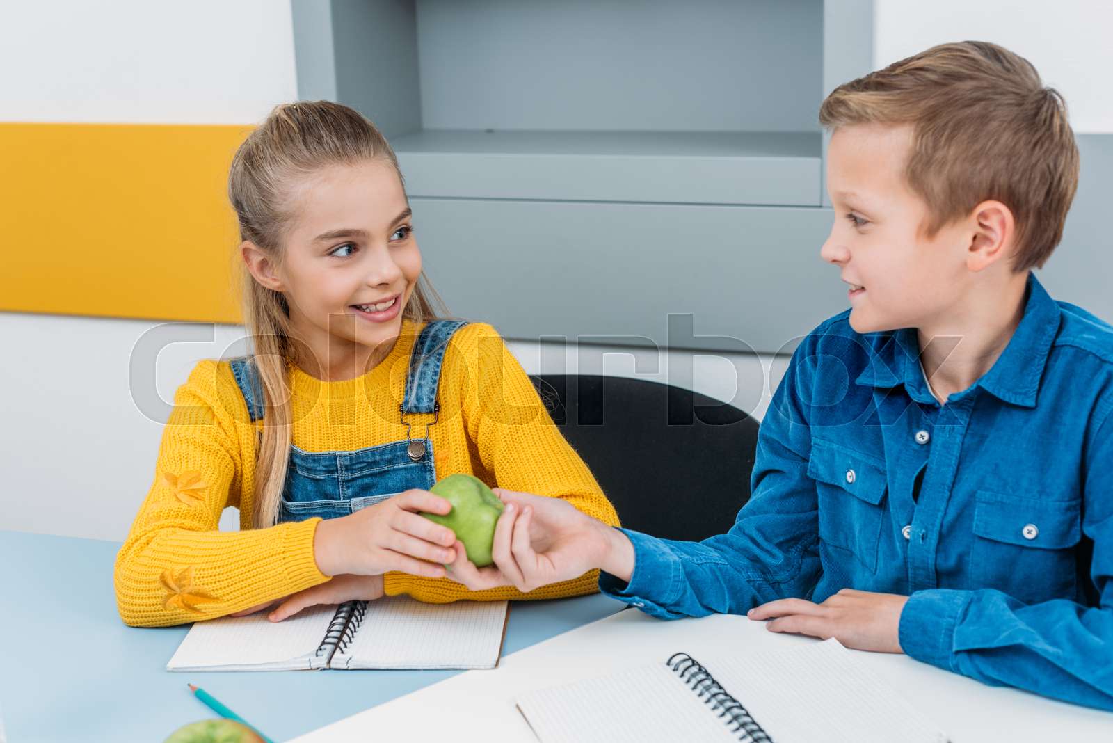 smiling classmates after lesson sharing apple | Stock image | Colourbox