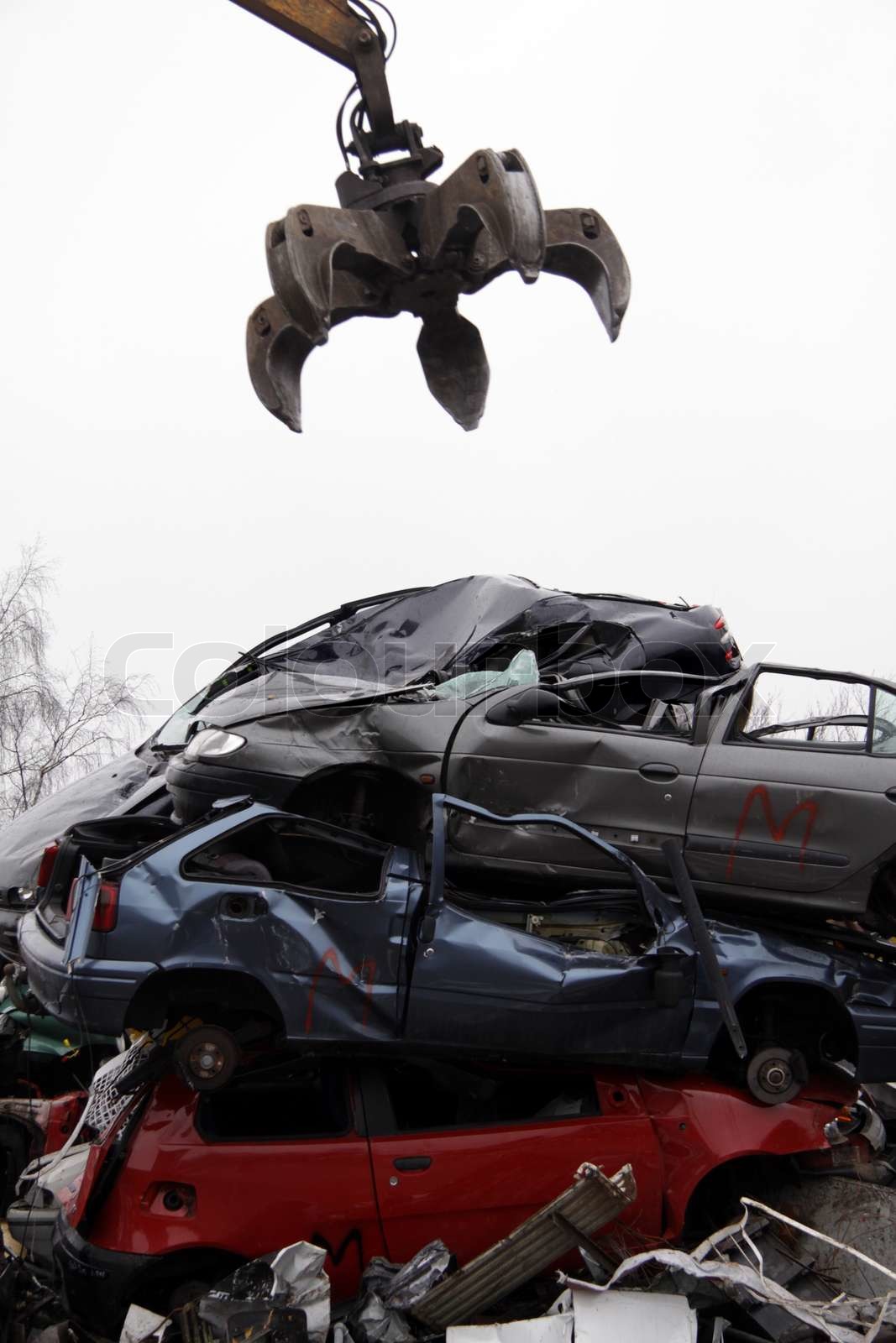 Car wreck being lifted by grab crane to be scrapped with other cars and ...