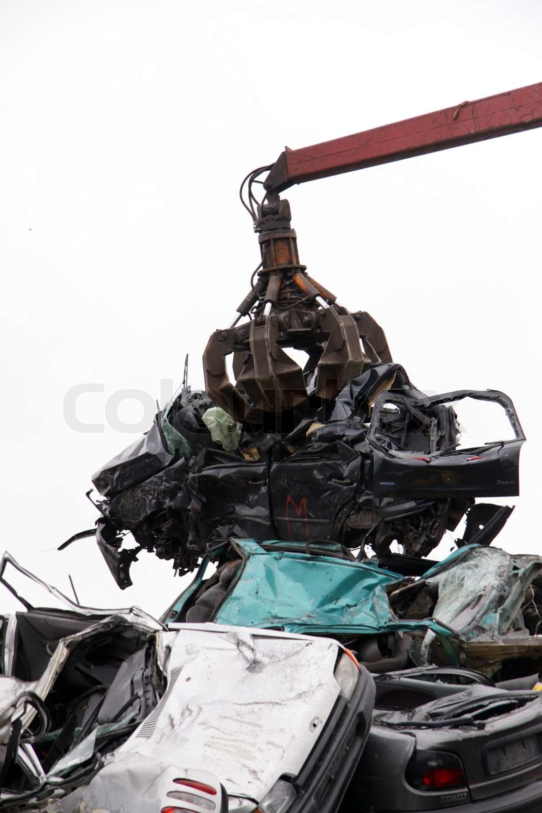 Car wreck being lifted by grab crane to be scrapped with other cars and ...