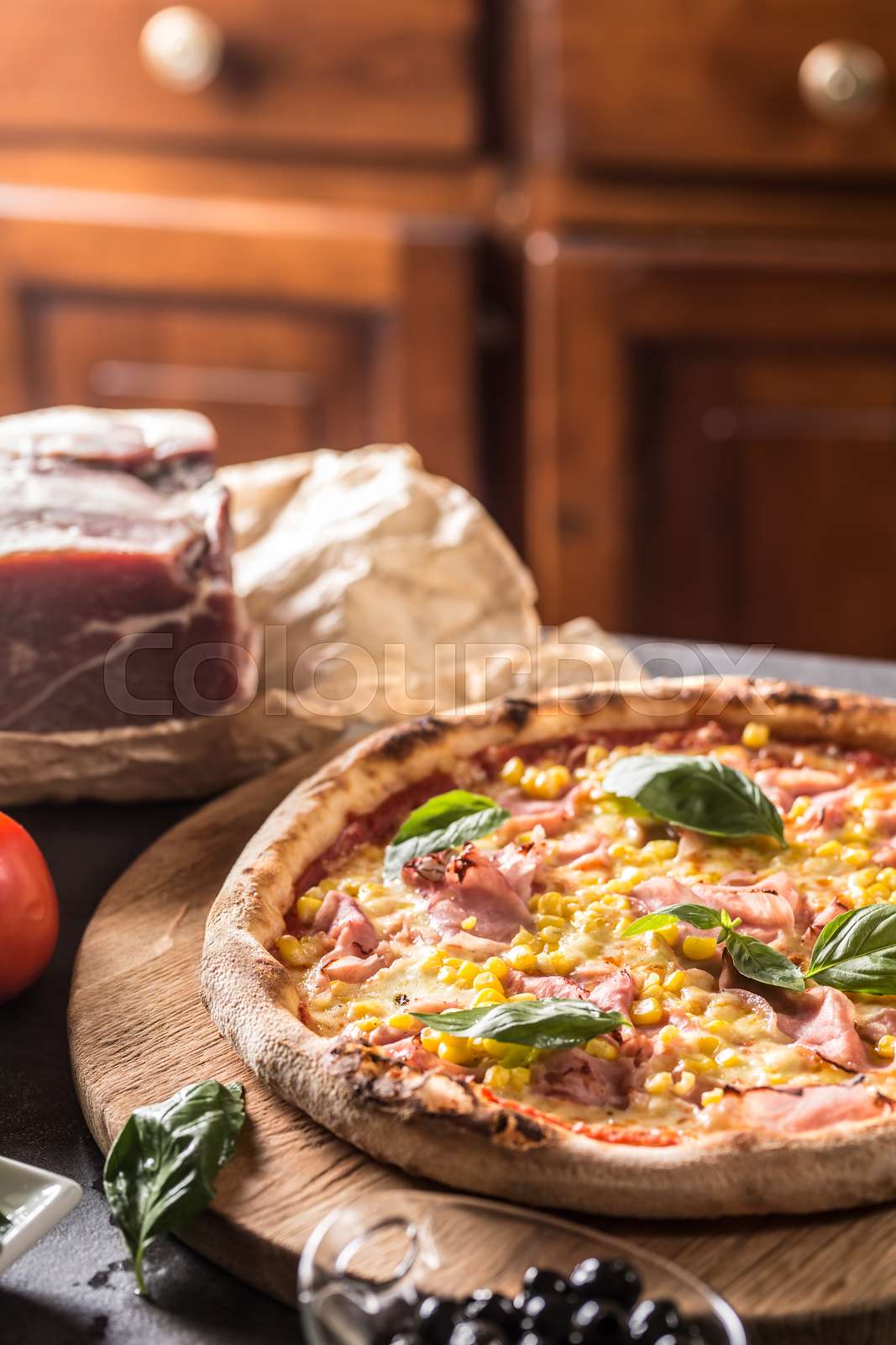 Italian pizza cardinale with ham prosciutto tomatoes corn and basil ...