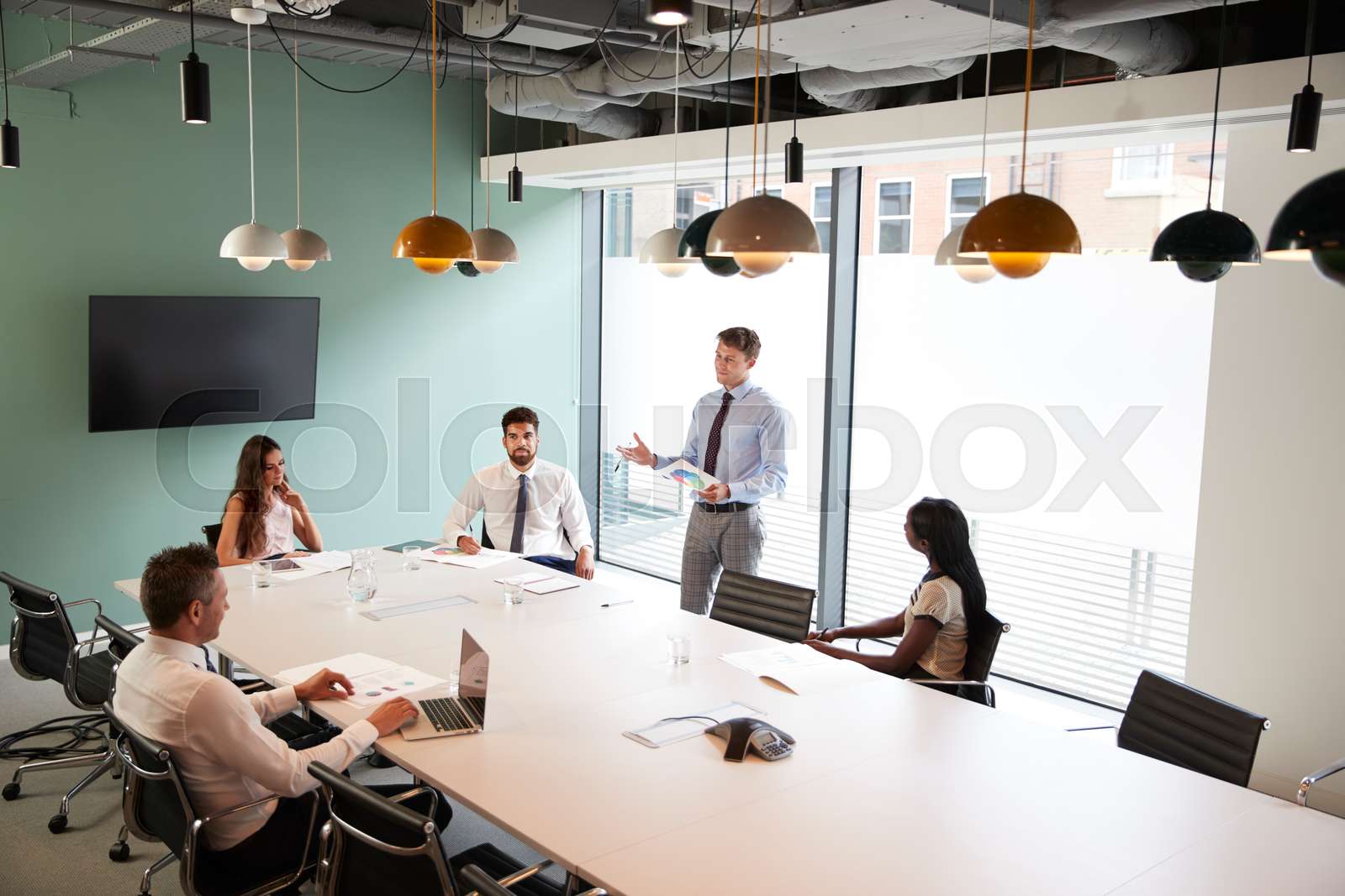 Businessman Giving Boardroom Presentation To Colleagues In Meeting Room ...