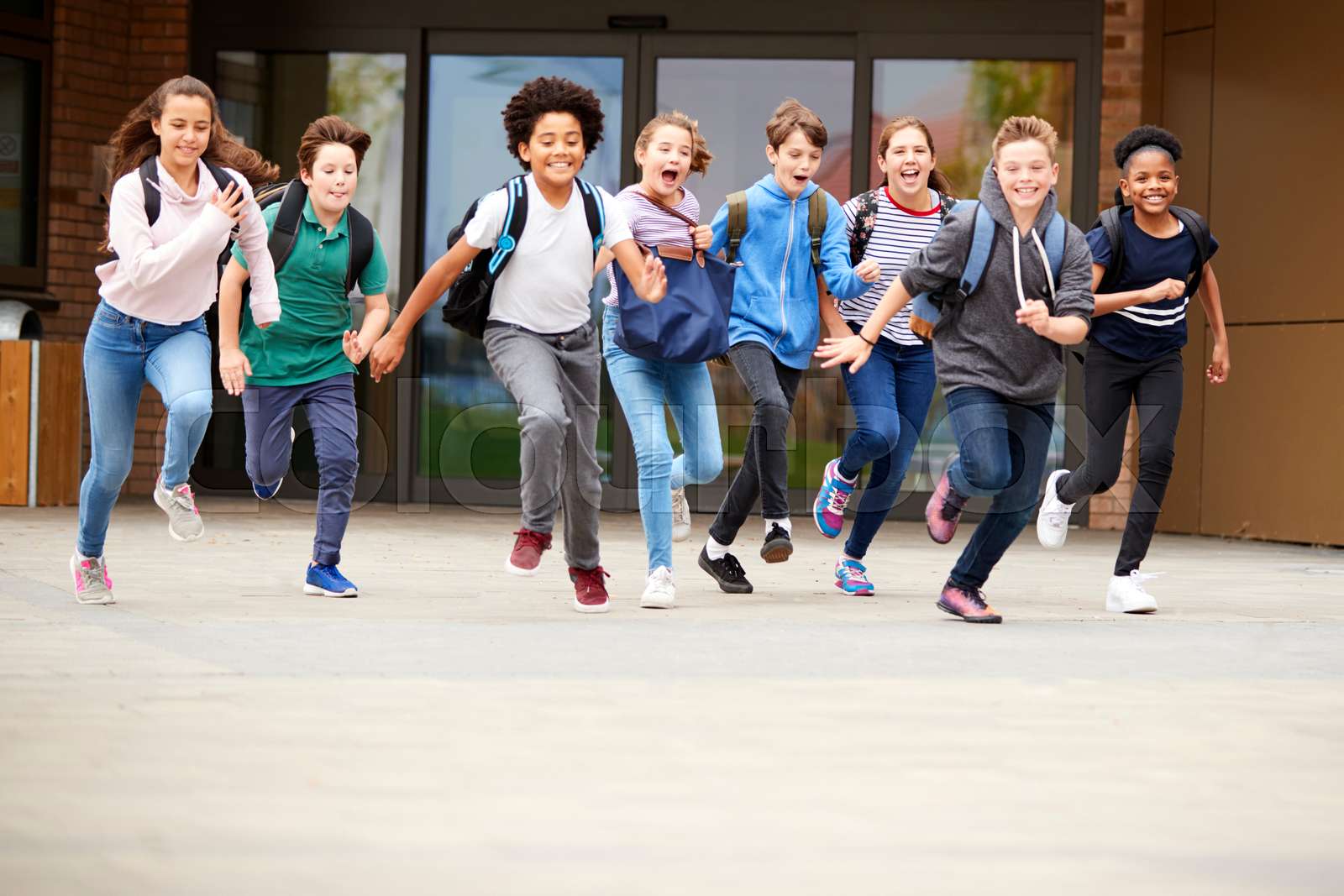 Group Of High School Students Running Out Of School Buildings Towards ...