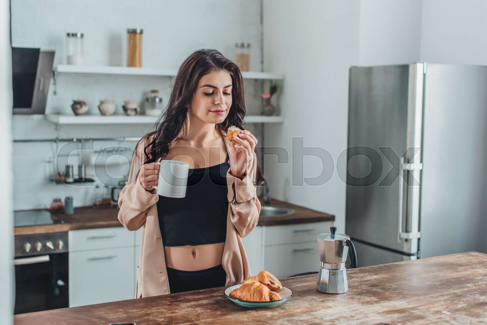 pretty girl having breakfast with croissants and coffee at wooden table ...