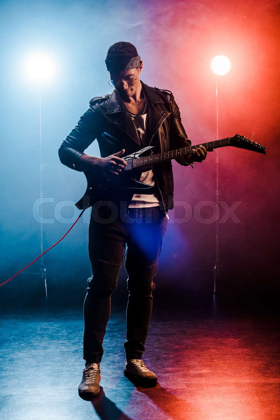 concentrated male rock star in leather jacket performing on electric ...