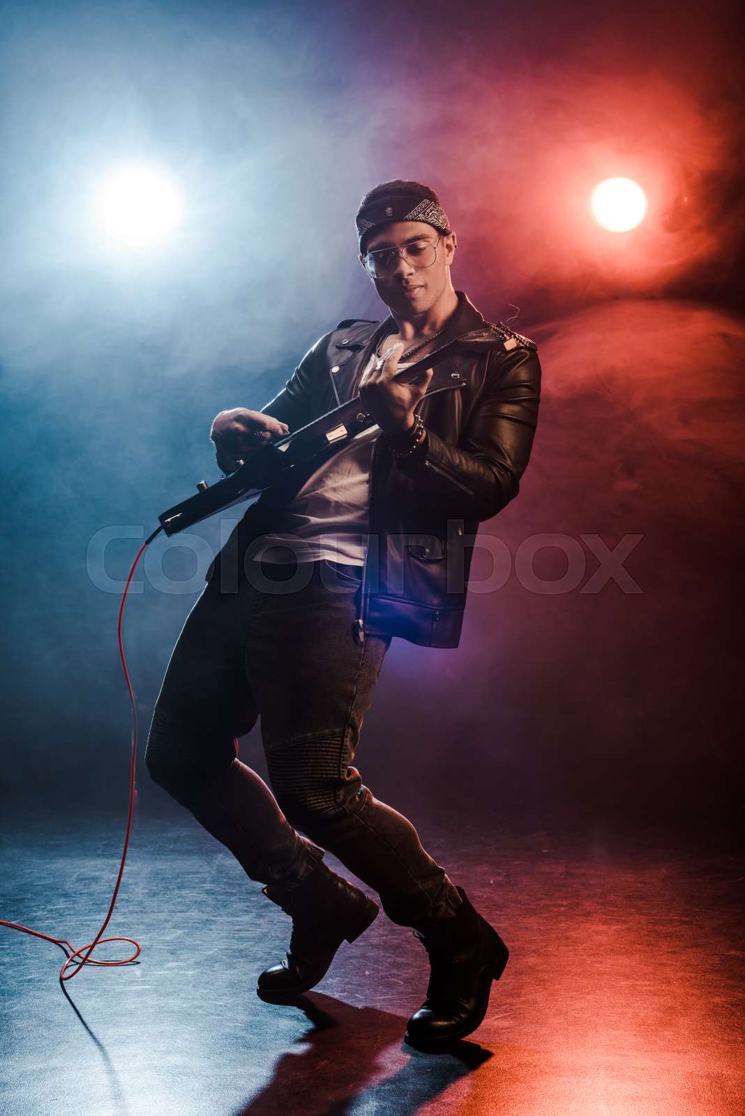 handsome stylish rocker in leather jacket performing on electric guitar ...