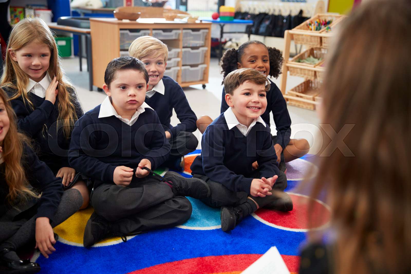 View over female teacher's shoulder of primary school kids sitting in ...