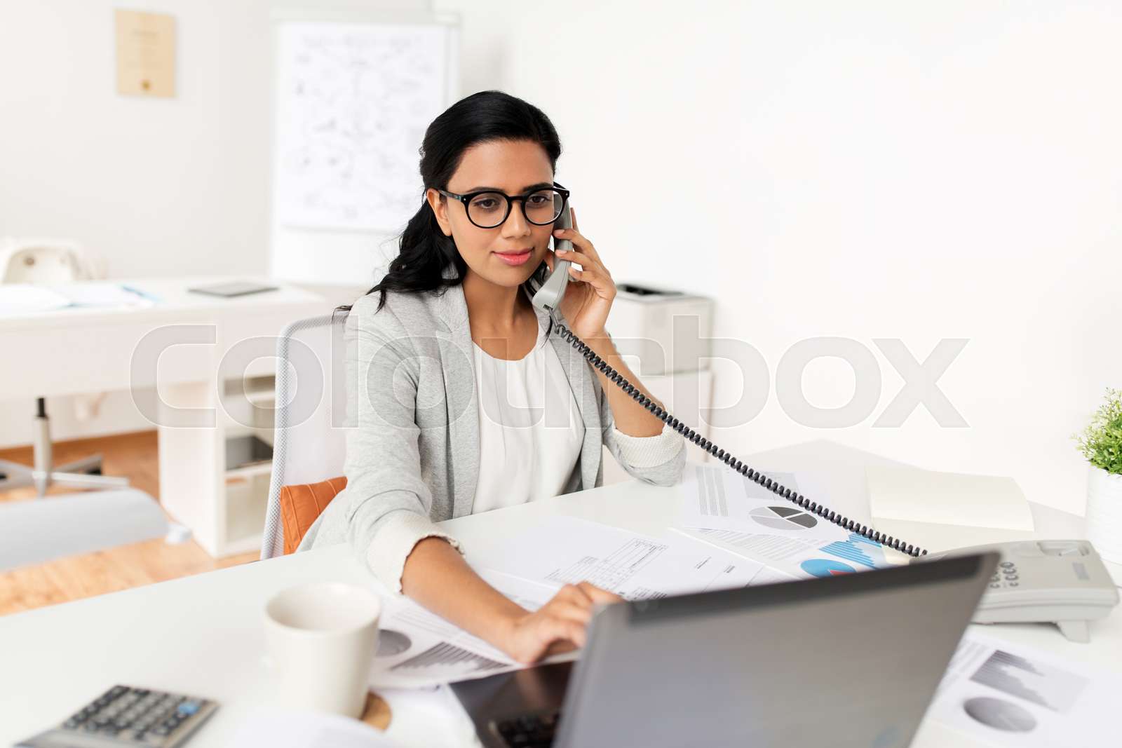 businesswoman calling on desk phone at office | Stock image | Colourbox