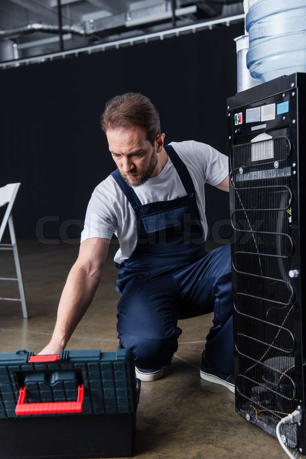adult male craftsman repairing water cooler and taking tools from ...