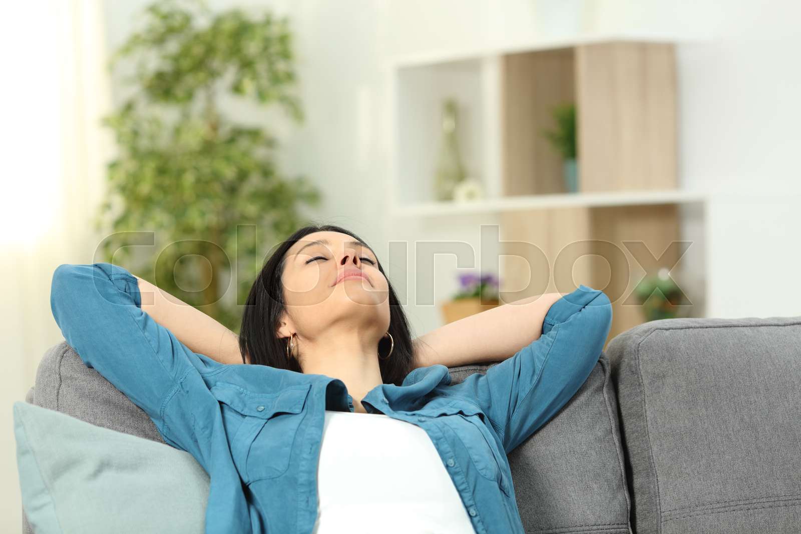 Relaxed woman resting sitting on a sofa at home | Stock image | Colourbox