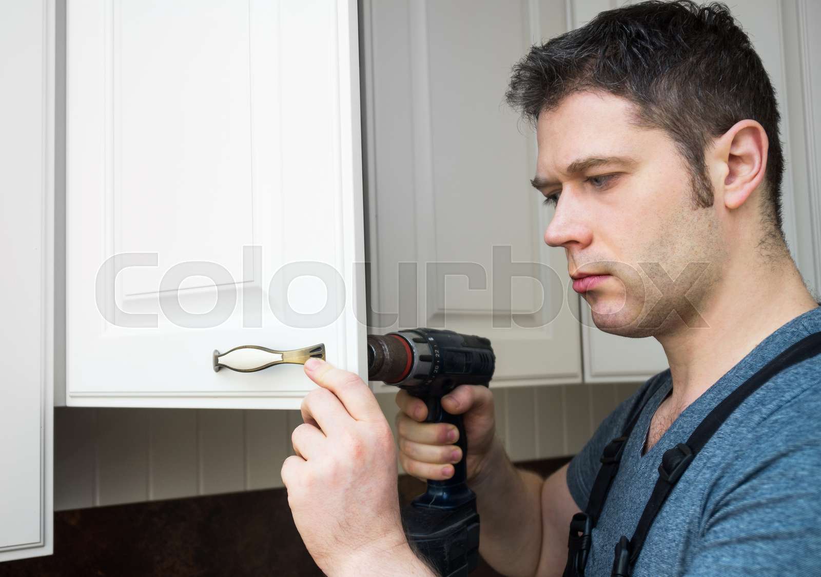 Professional handyman assembling kitchen door cabinet. | Stock image ...