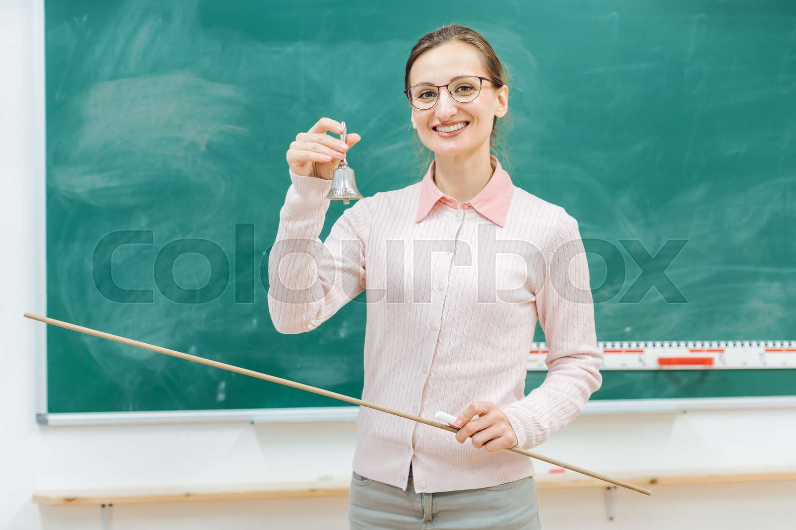 Teacher ringing the bell for class to begin | Stock image | Colourbox
