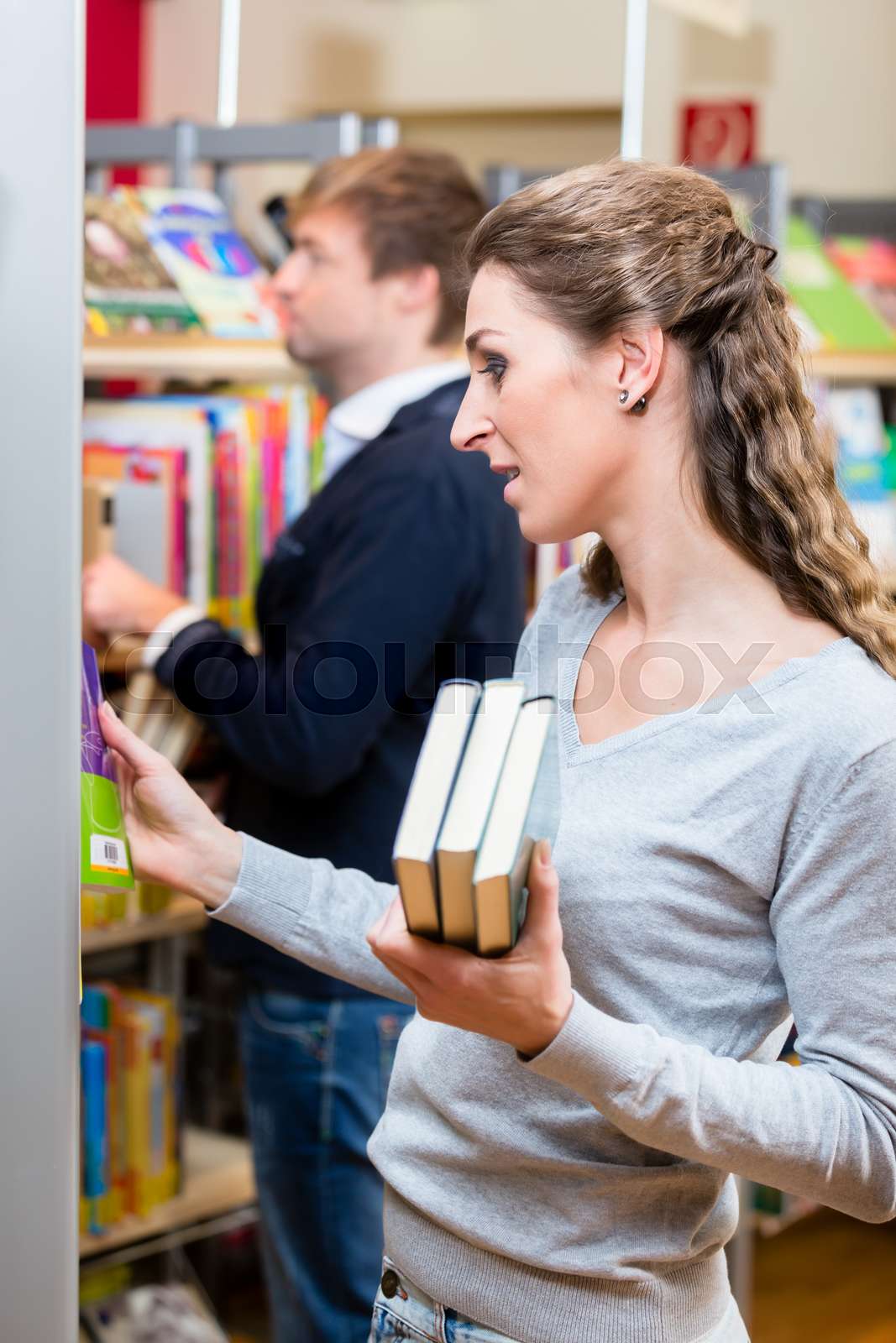 Woman choosing books from shelf in library | Stock image | Colourbox
