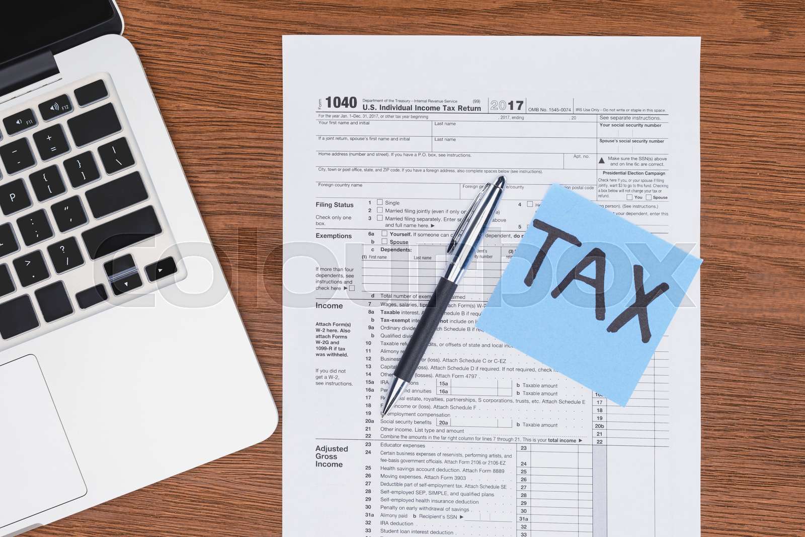 top view of tax form, laptop and blue card with 'tax' word on desk ...