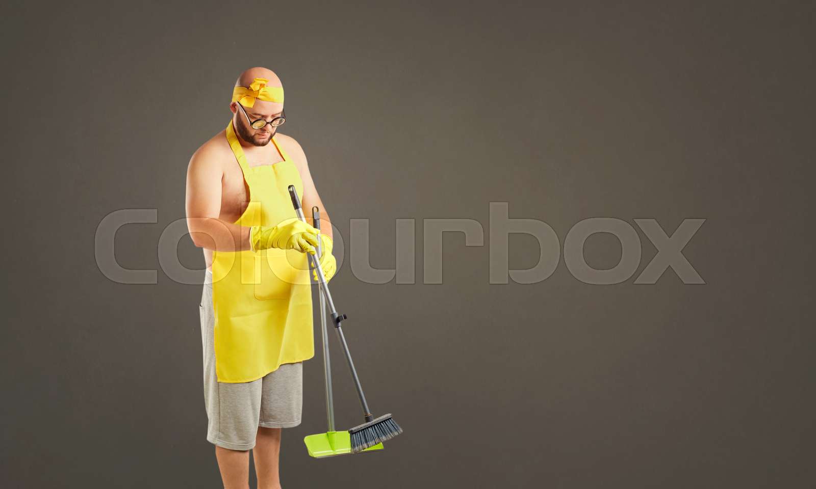 Funny fat cleaning man in an apron on cleaning. | Stock image | Colourbox