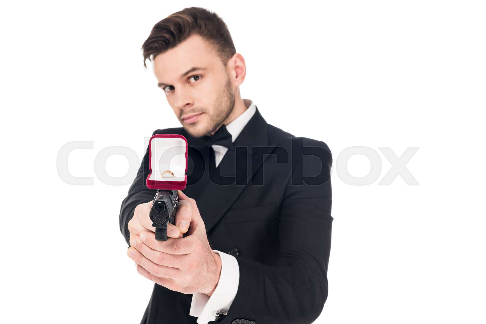 handsome secret agent in black suit aiming with handgun with proposal ring, isolated on white ...