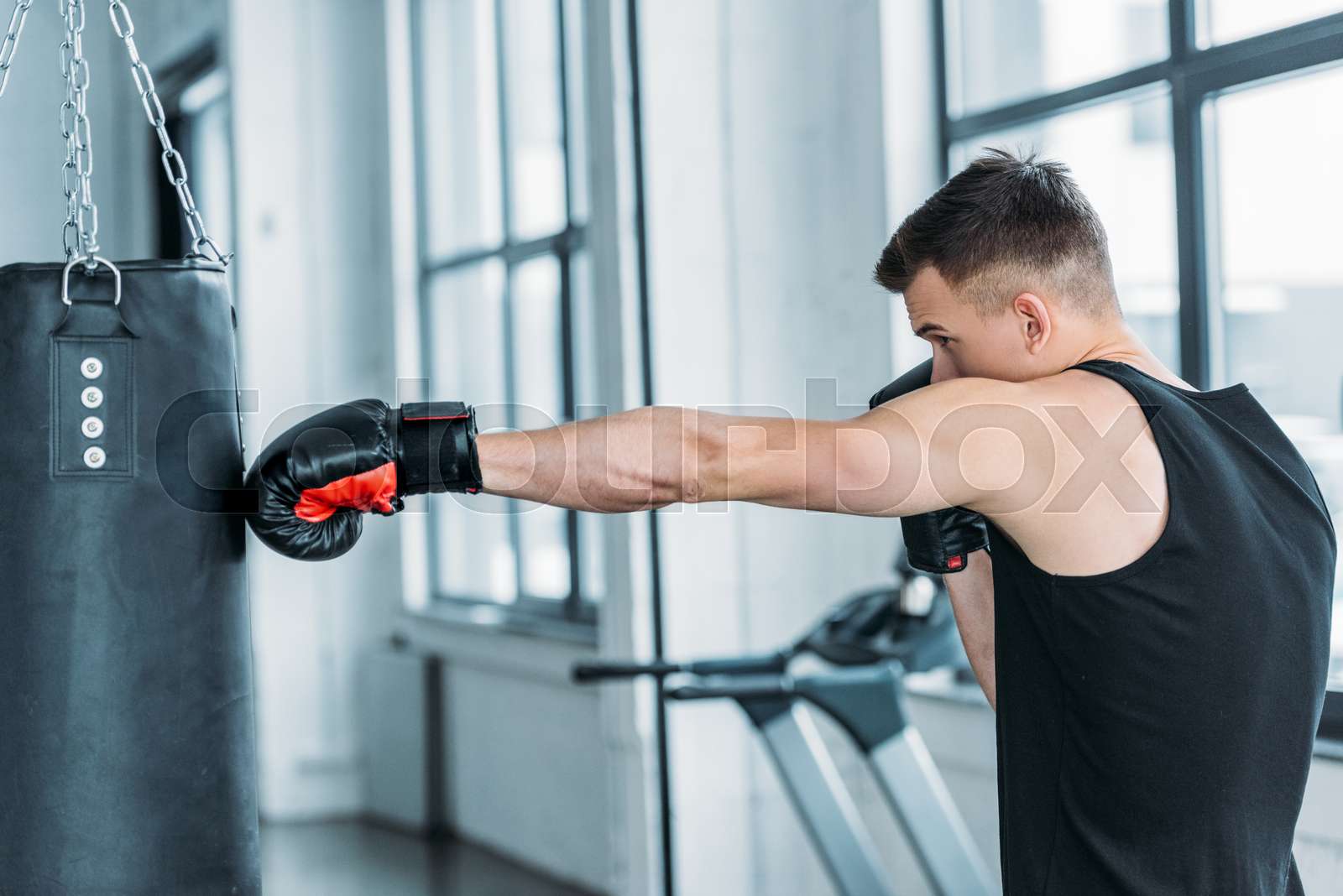 side view of muscular young man boxing with punching bag in gym | Stock ...