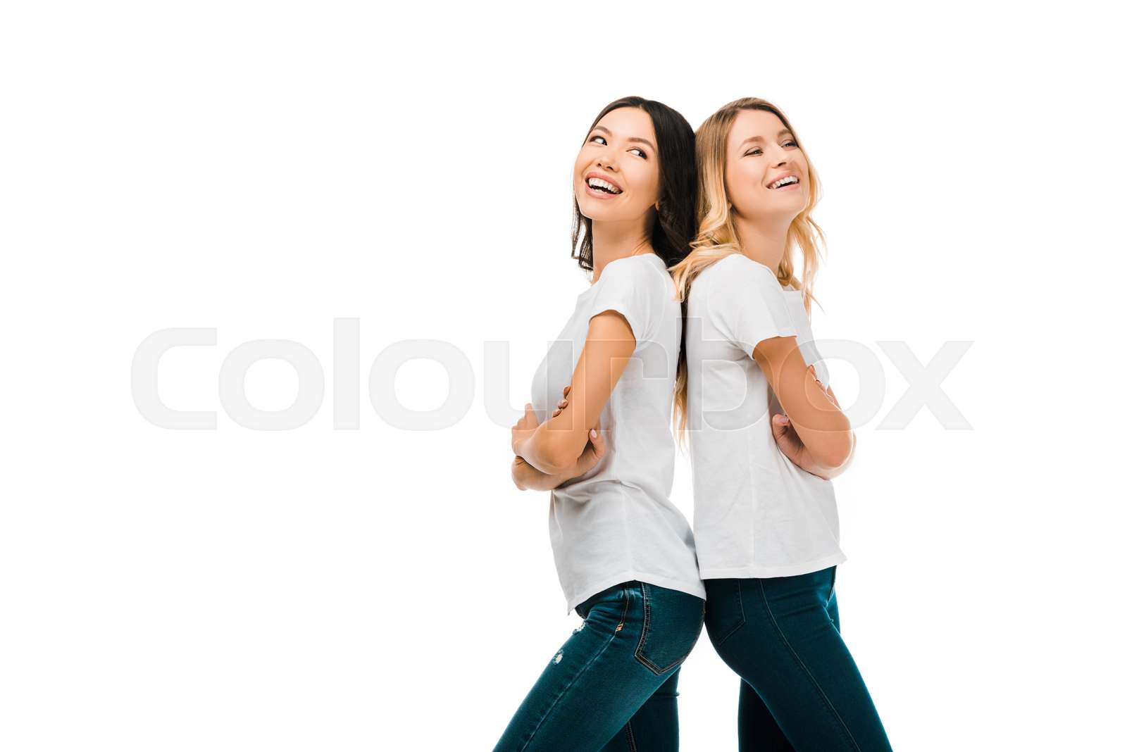 side view of beautiful happy young women standing back to back and ...