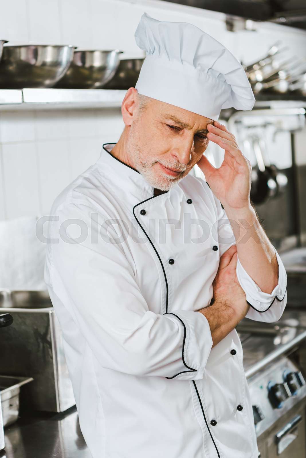 tired male chef in uniform touching head and having headache in ...