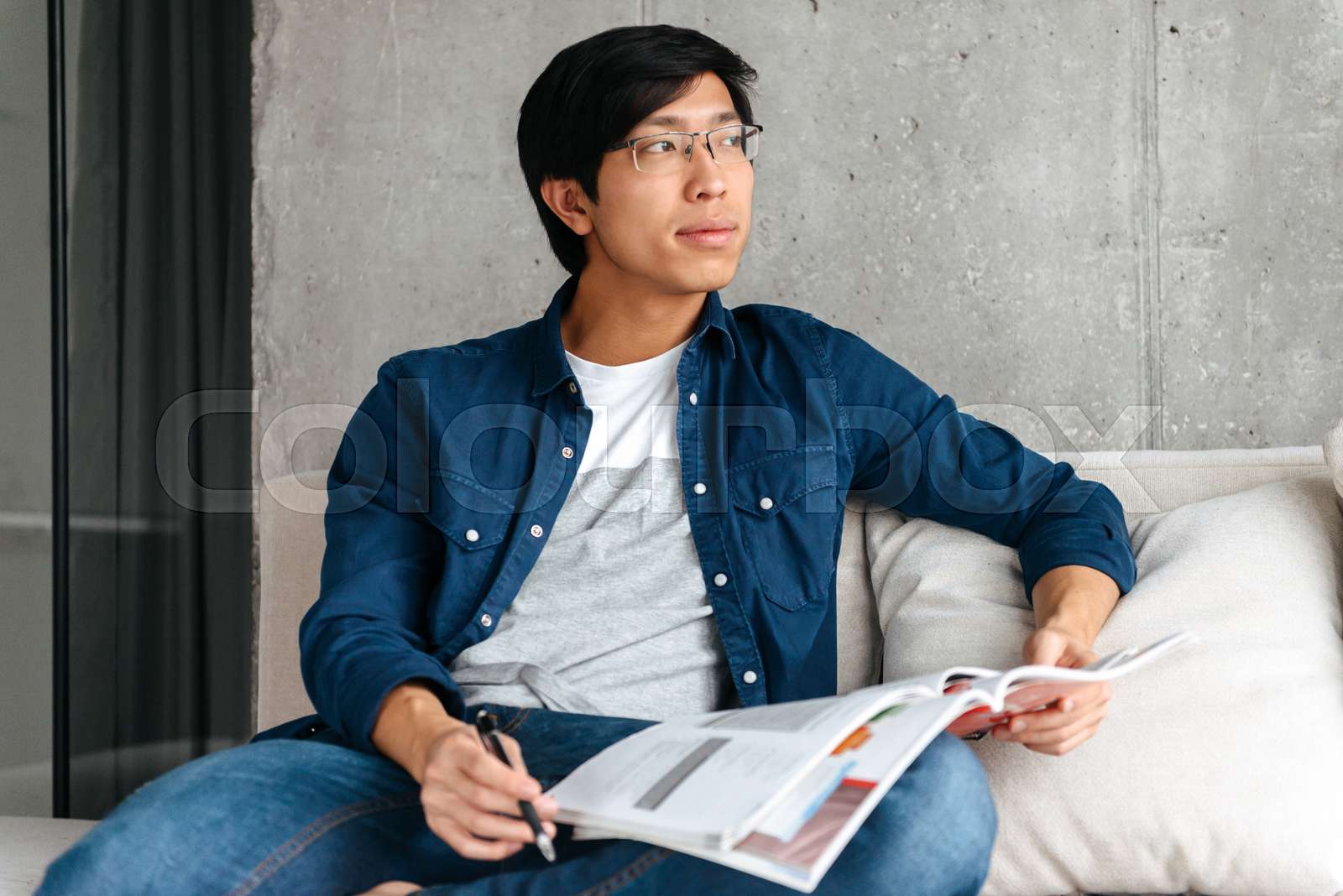 Confident smiling asian man sitting on a couch | Stock image | Colourbox