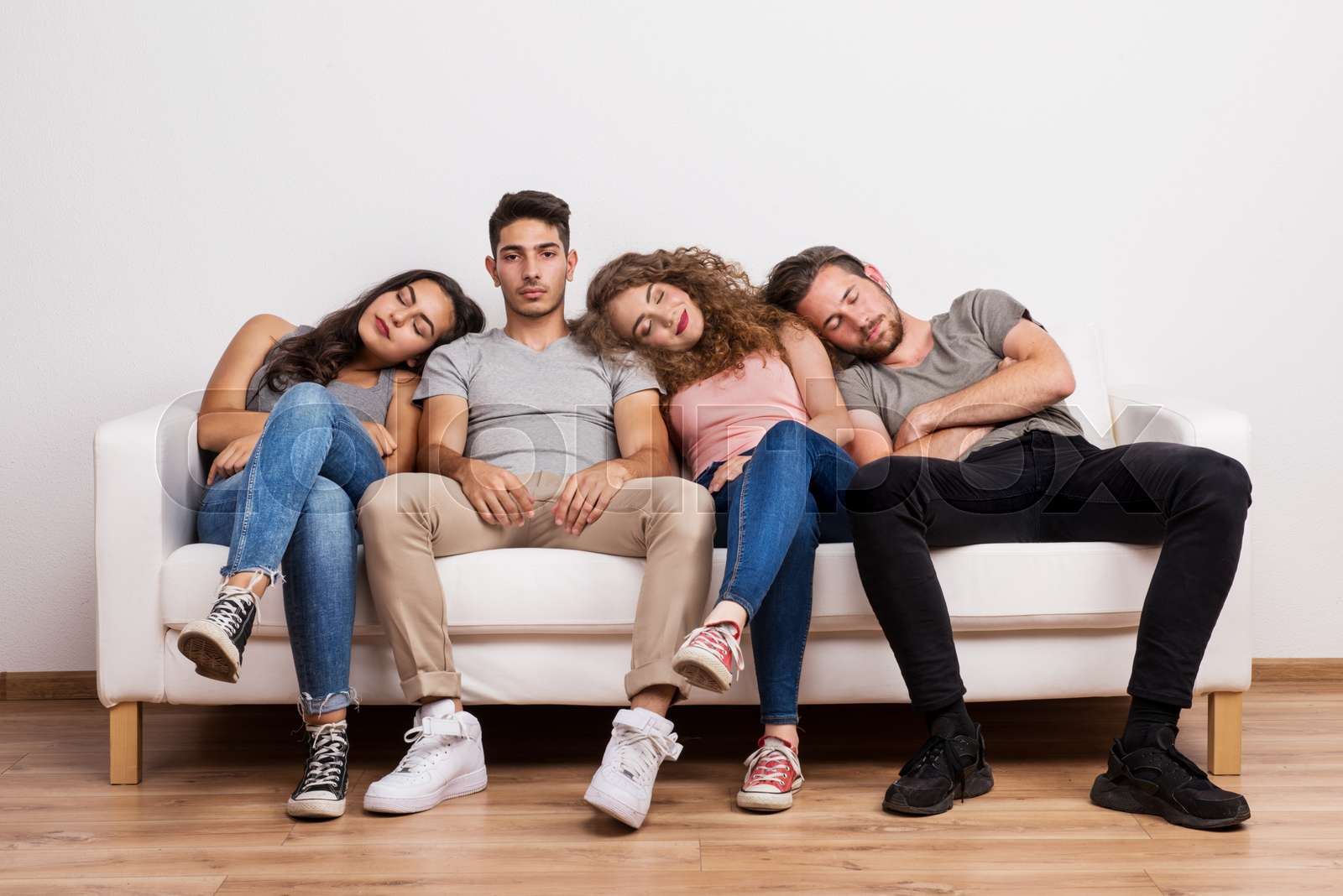Portrait of young group of friends sitting on a sofa in a studio ...