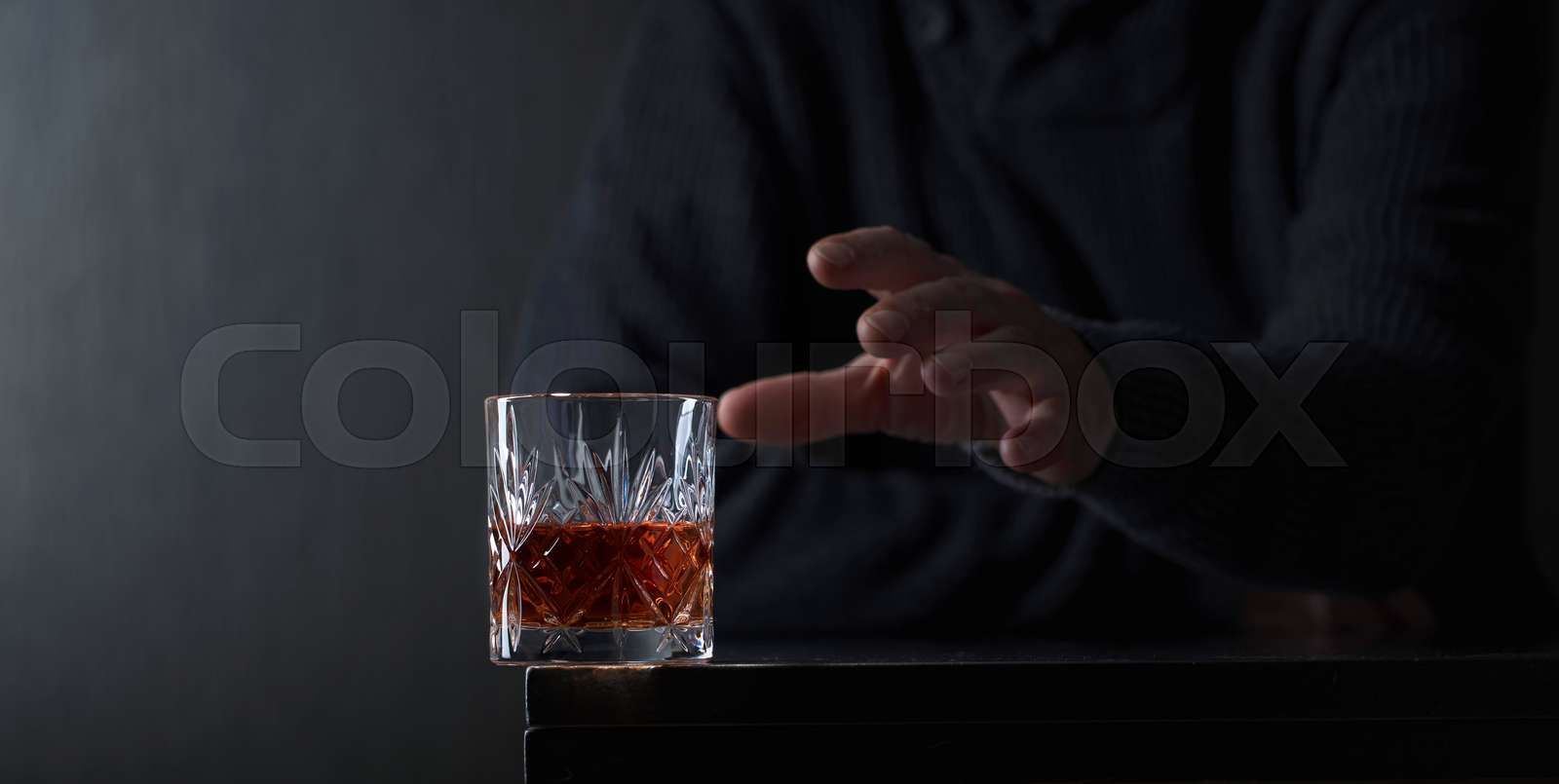 Man's hand reaches for a glass of alcohol. | Stock image | Colourbox