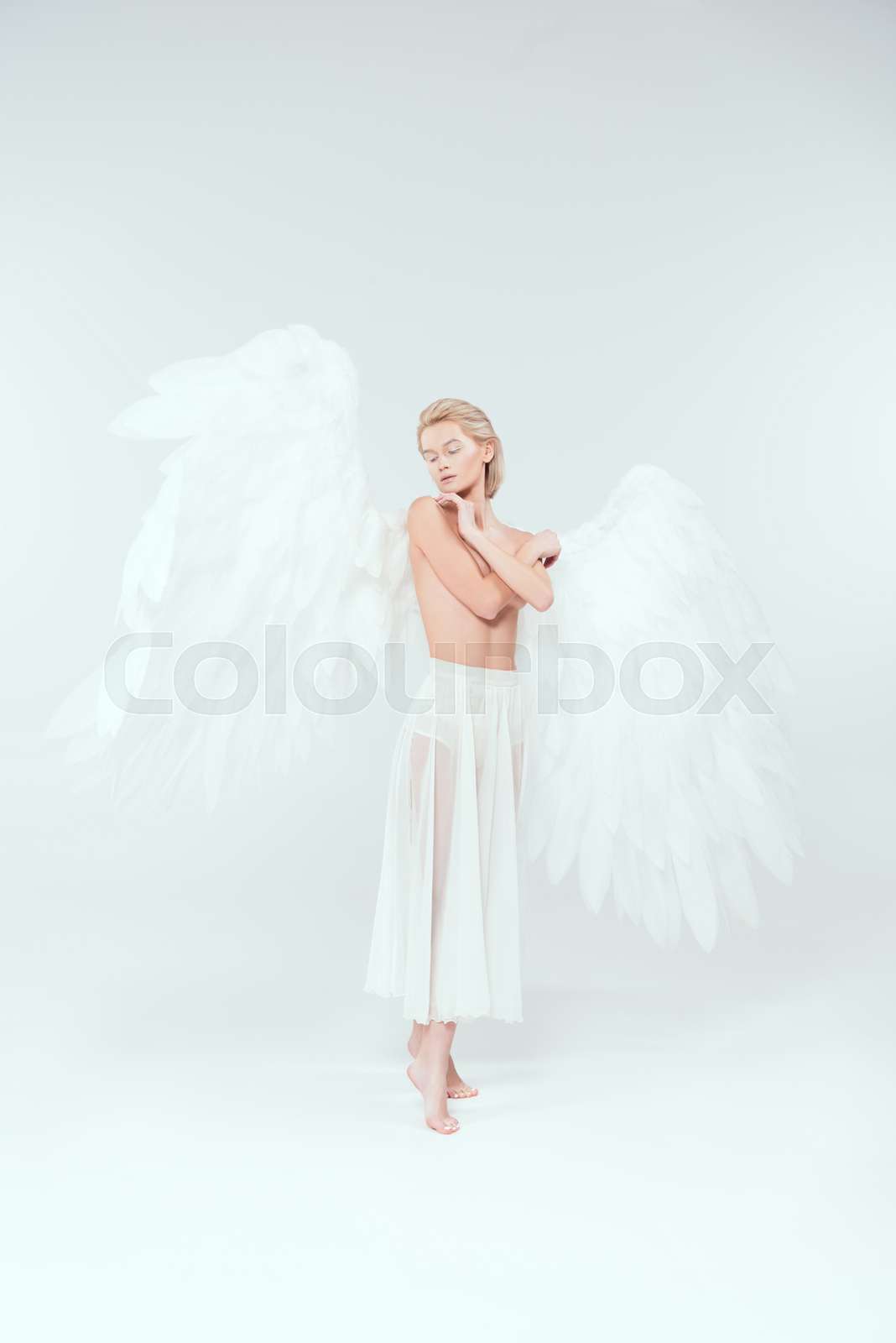 beautiful woman with angel wings covering breasts and posing with eyes ...