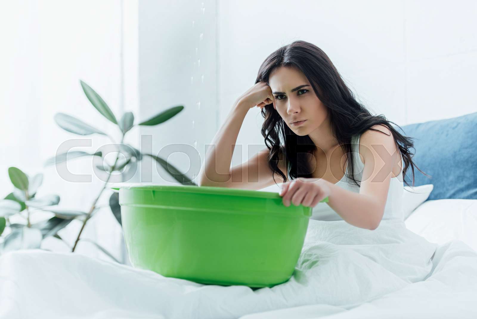 Sad woman sitting in bed with basin during water leak | Stock image ...
