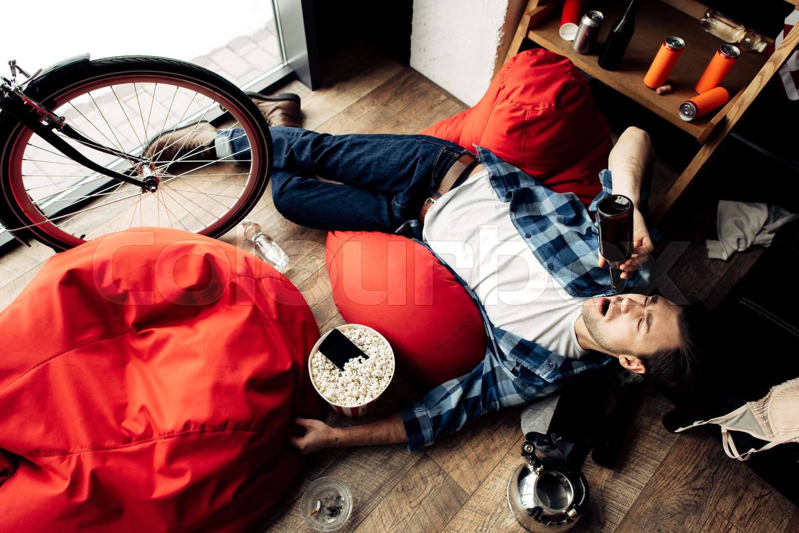 drunk man lying on bean bag and drinking beer | Stock image | Colourbox
