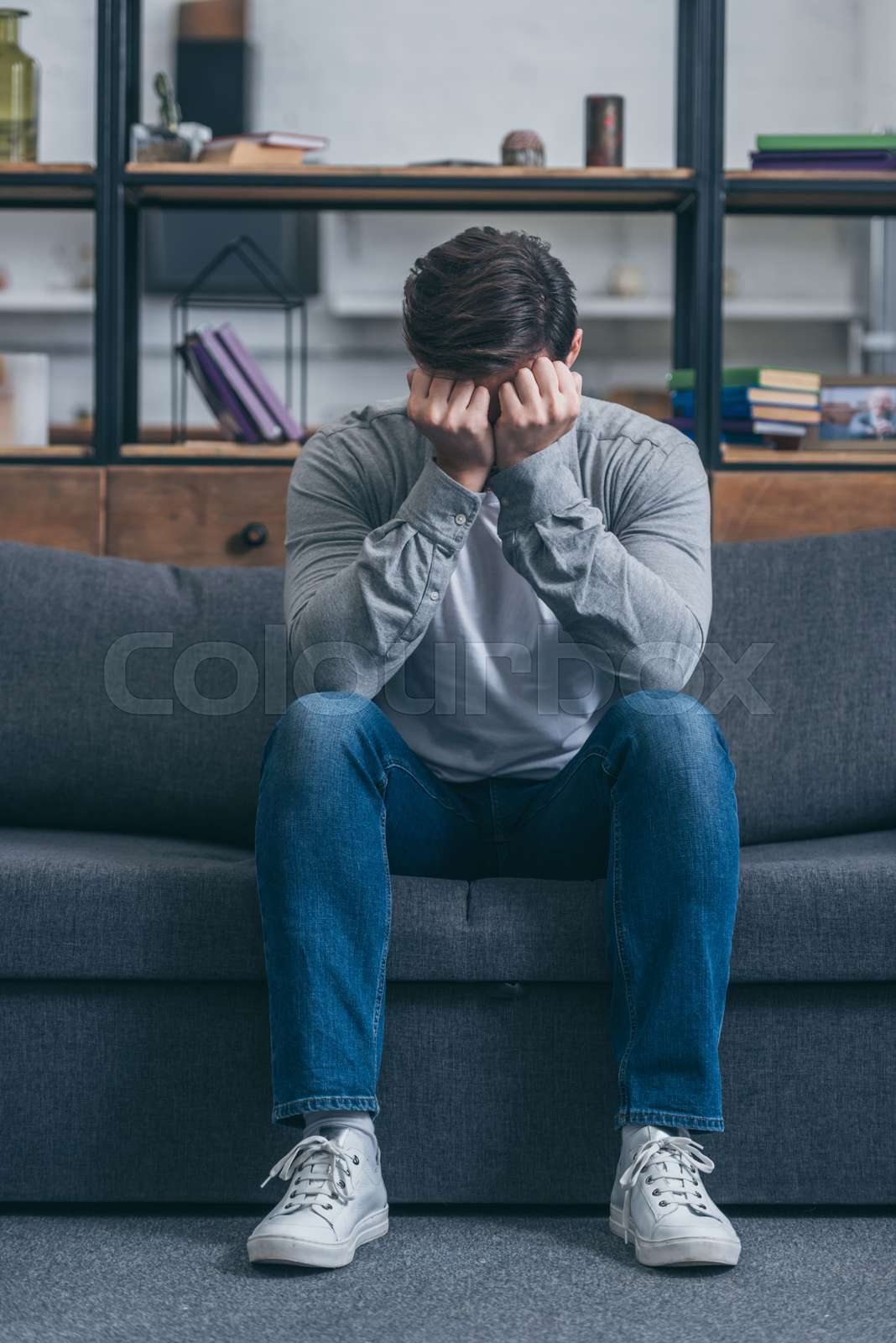 sad man sitting on couch and covering face with hands at home, grieving ...