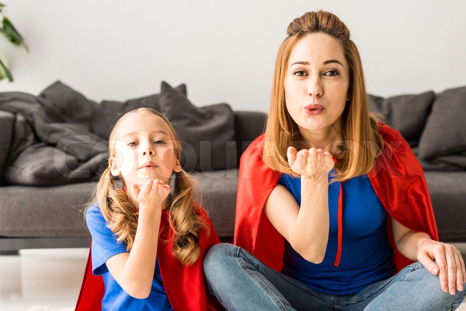 daughter and mother in red cloaks blowing air kisses | Stock image ...
