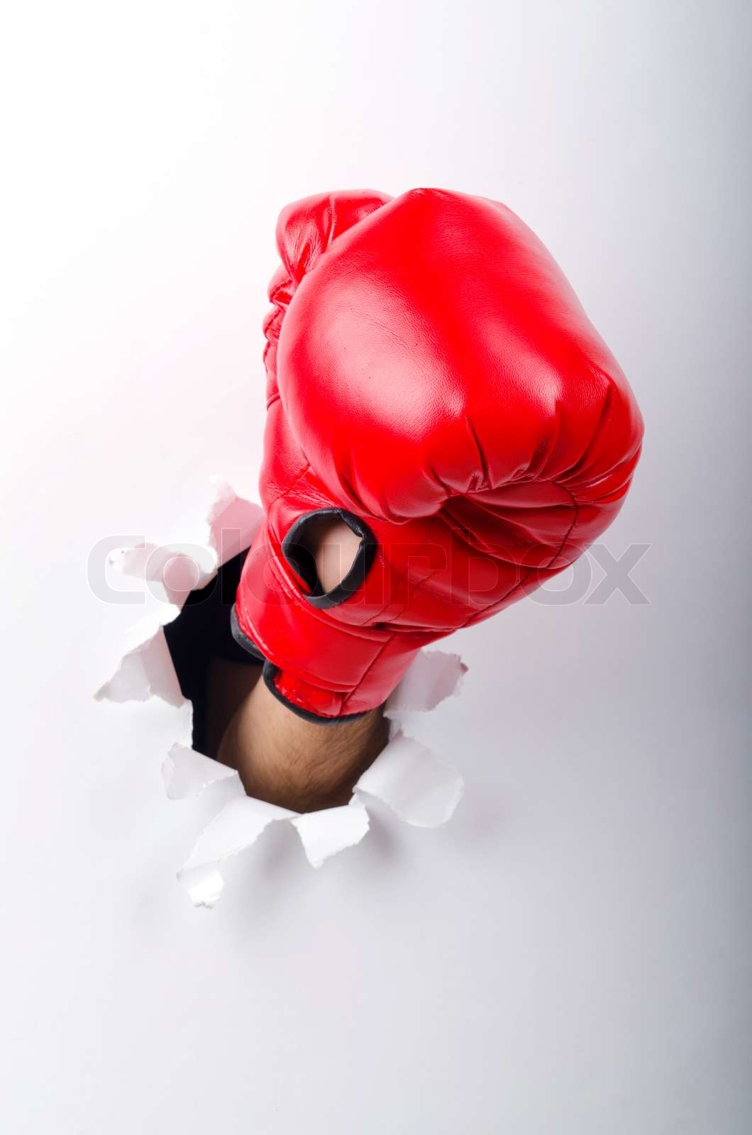 Hand in boxing glove through paper hole | Stock image | Colourbox