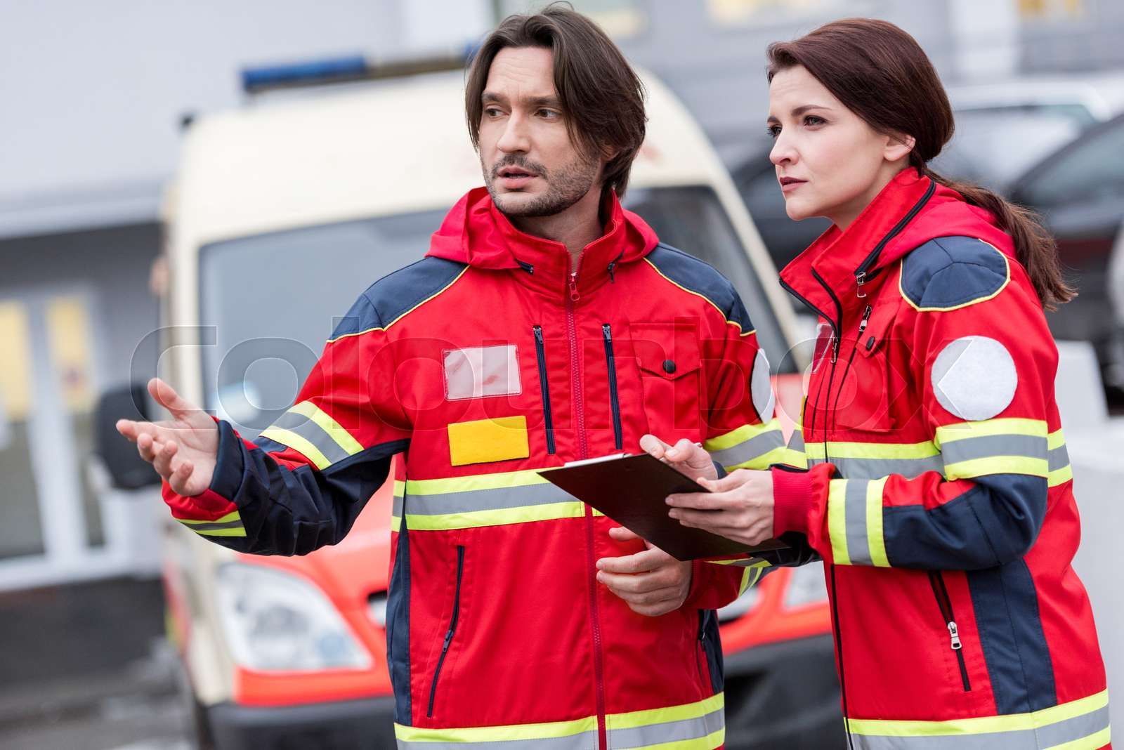 Paramedics in red uniform talking and looking away on street | Stock ...