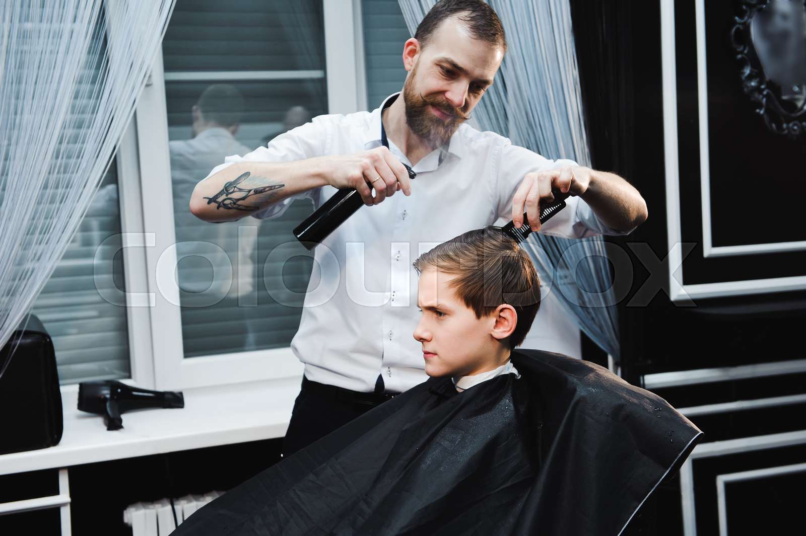Cute young boy getting a haircut in barbershop. | Stock image | Colourbox