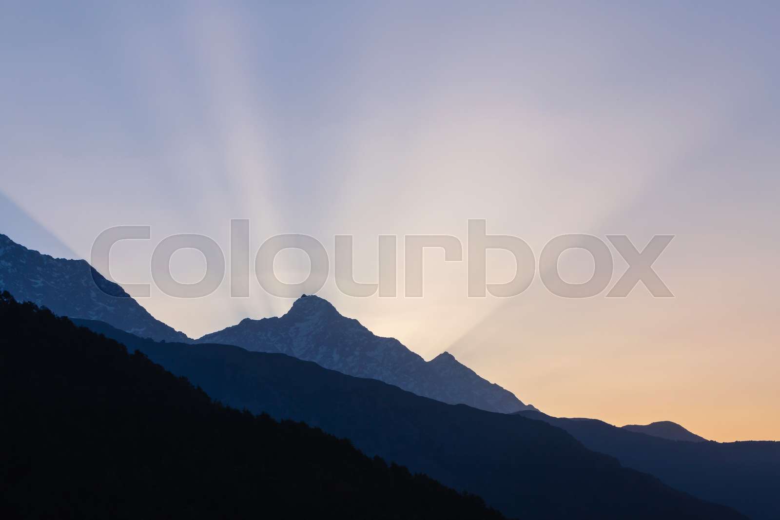 rays of rising sun behind mountain in Himalayas, India | Stock image ...