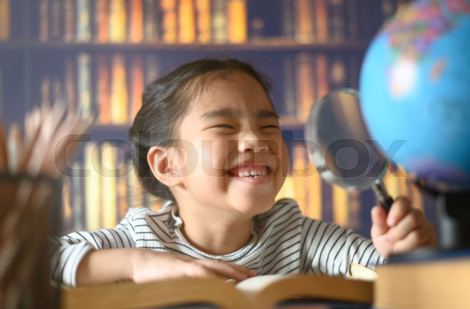 asian child girl industrious is sitting at a desk indoors. Kid is ...