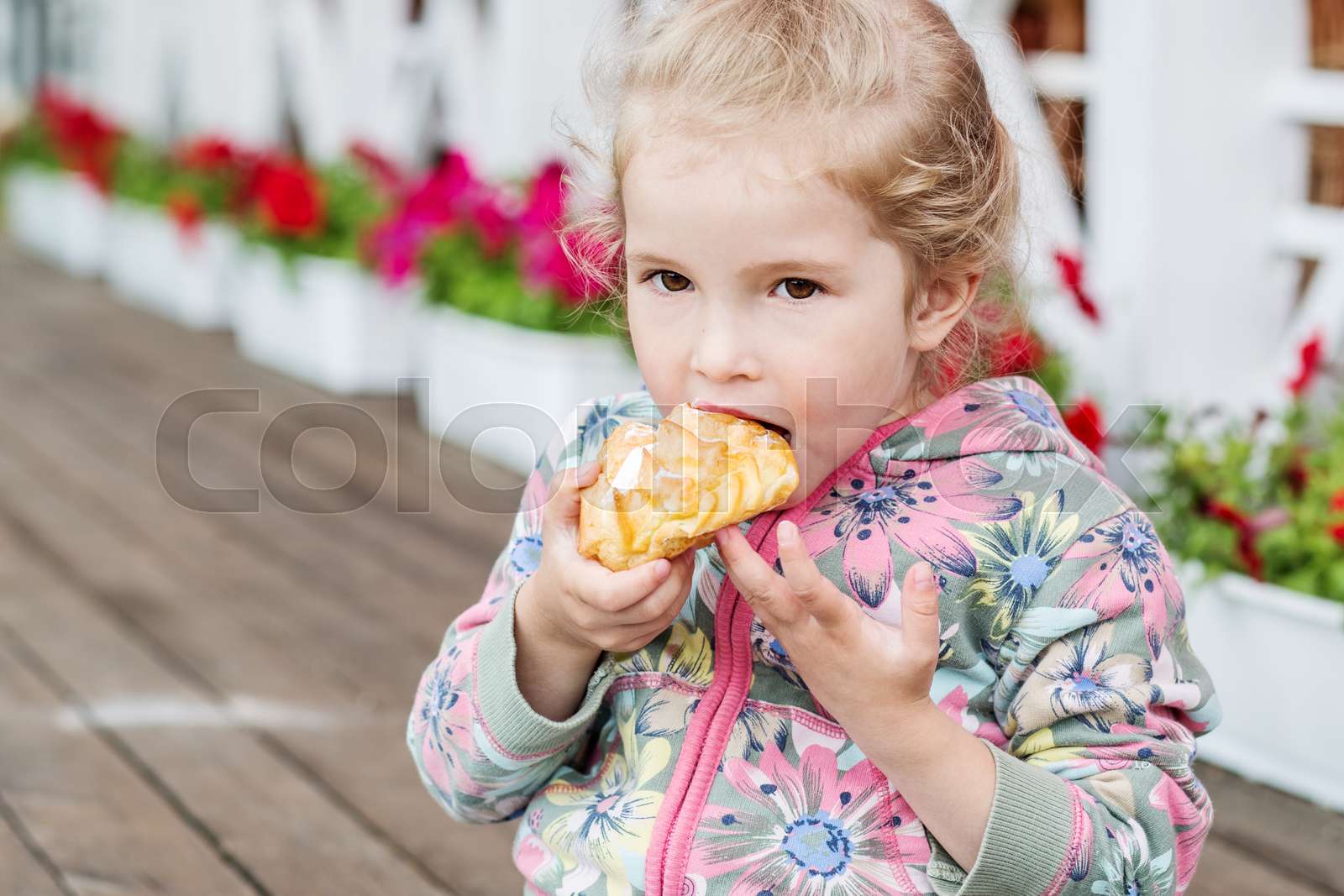 cute little girl eating eclair | Stock image | Colourbox