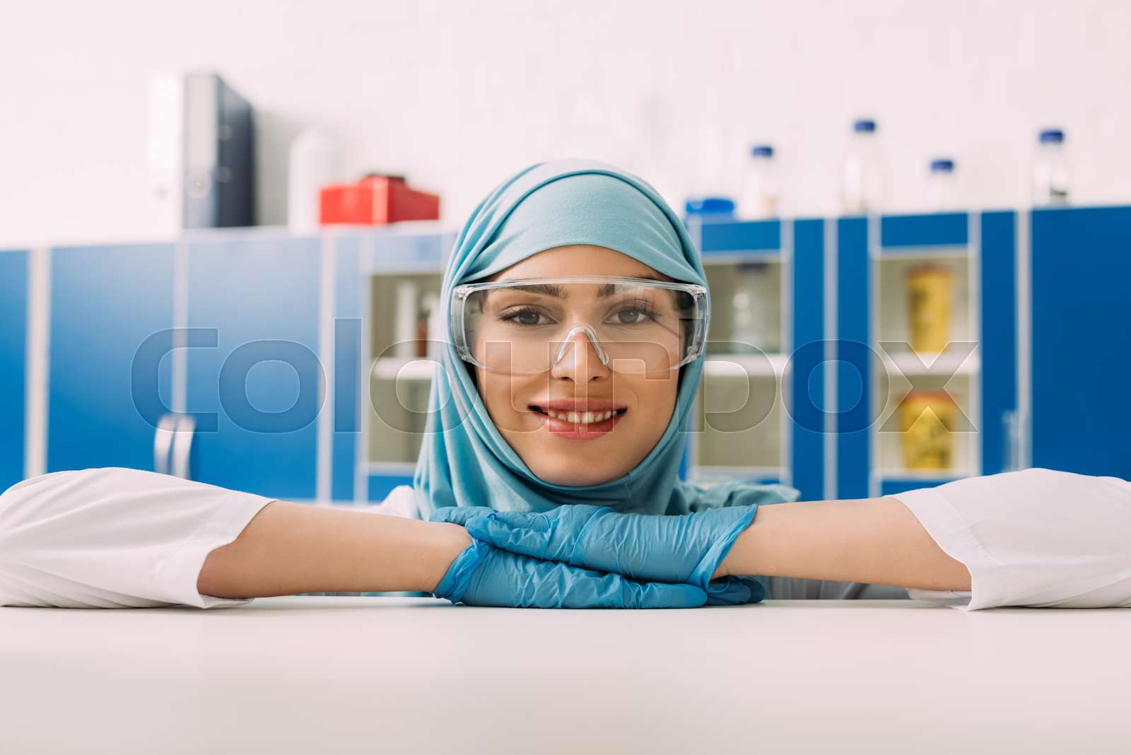smiling female muslim scientist in latex gloves, goggles and hijab ...