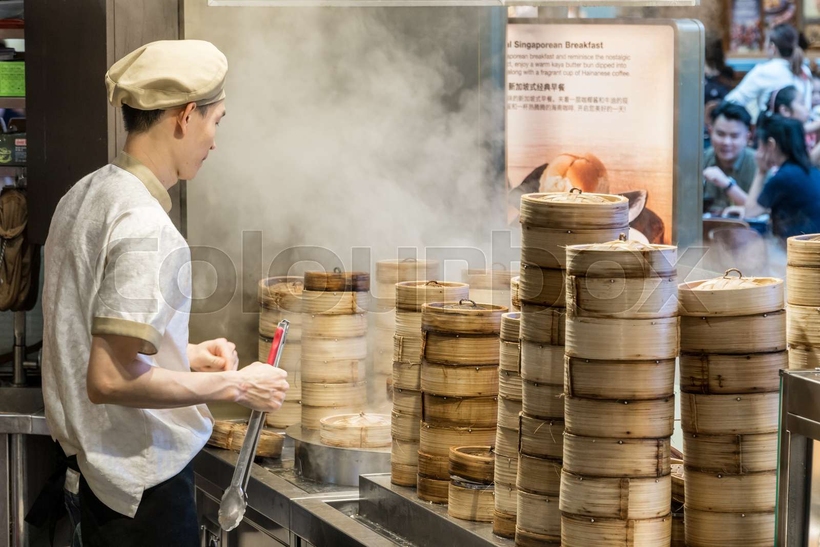 Vendor is preparing steamed dim sums in bamboo trays on a food court ...