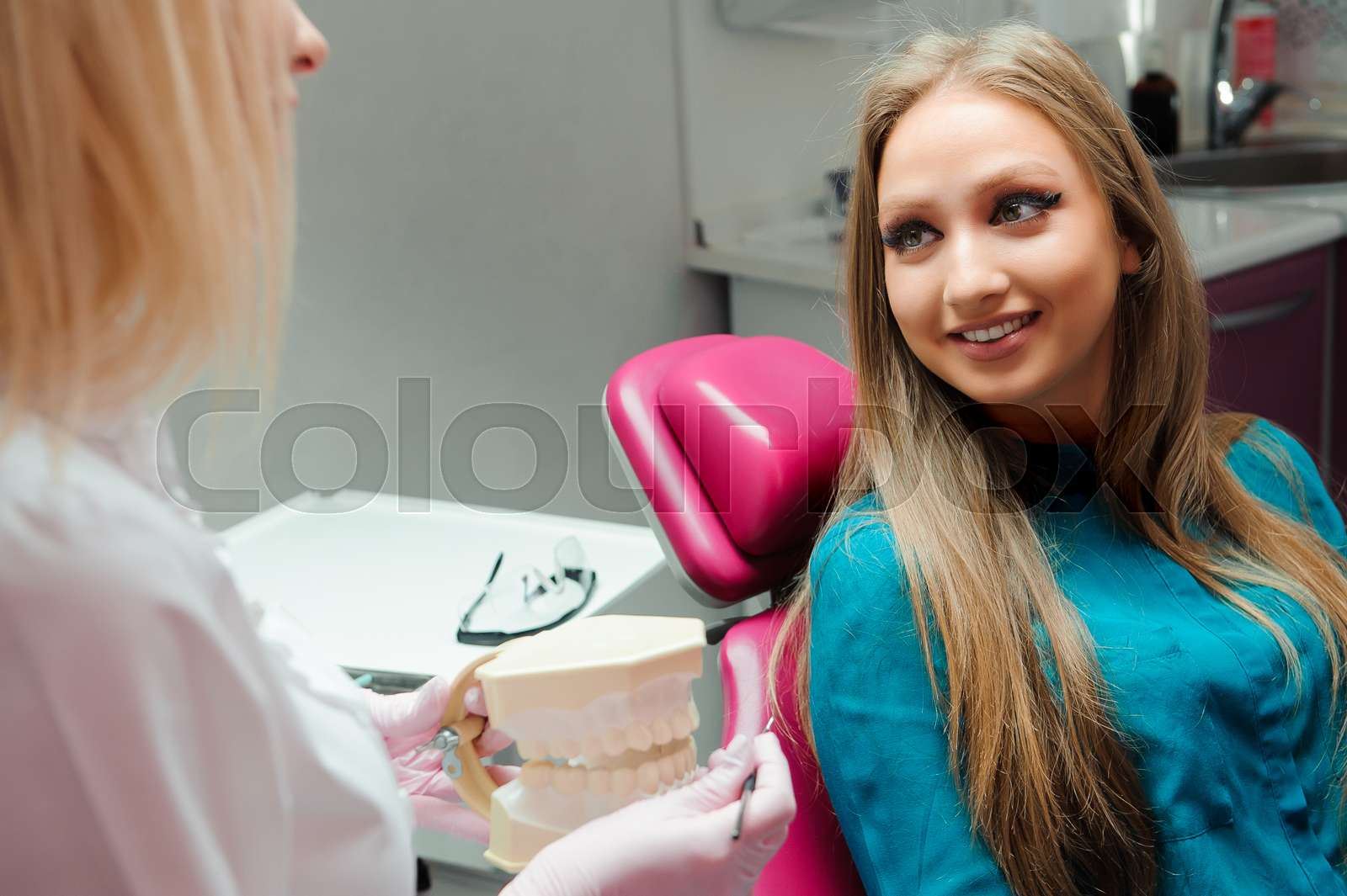 Dentist in dental office talking with a patient and preparing for ...