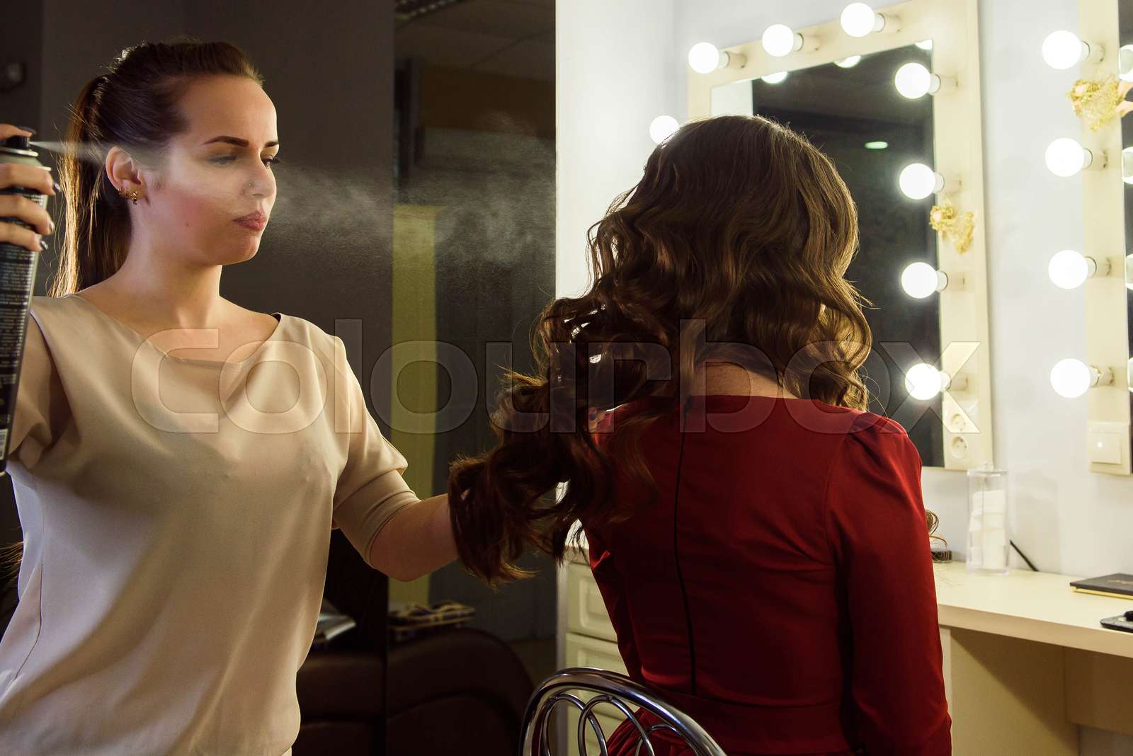 Master stylist makes model hairstyle using spray lacquer fixing ...