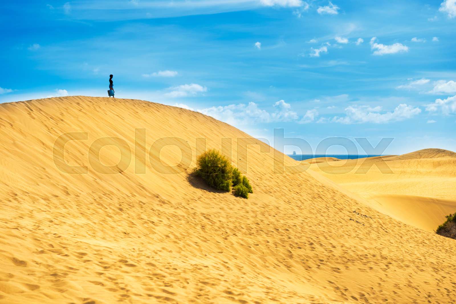 Sandy landscape with woman on top of dune | Stock image | Colourbox