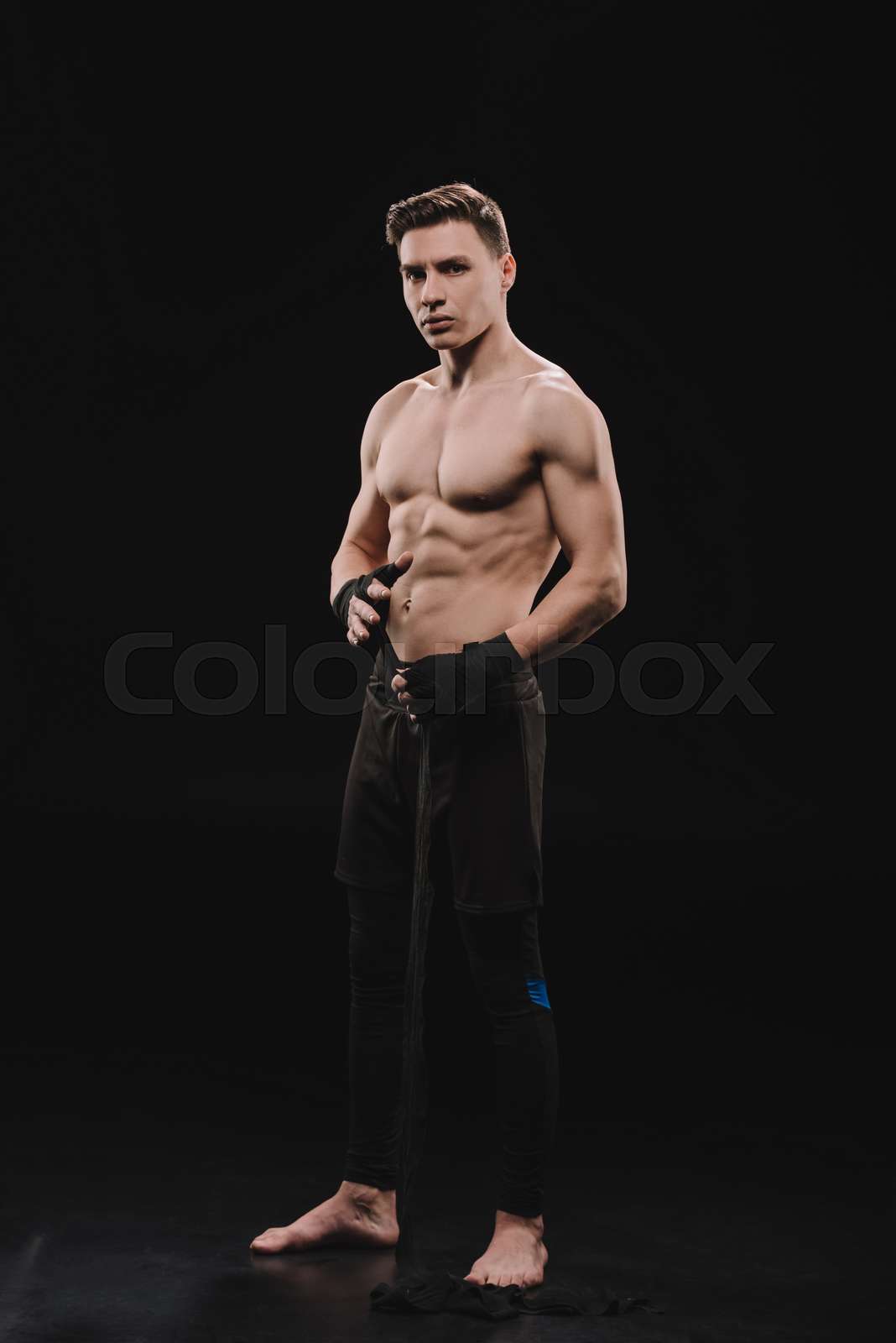 strong barefoot muscular mma fighter fixing bandages and looking at ...