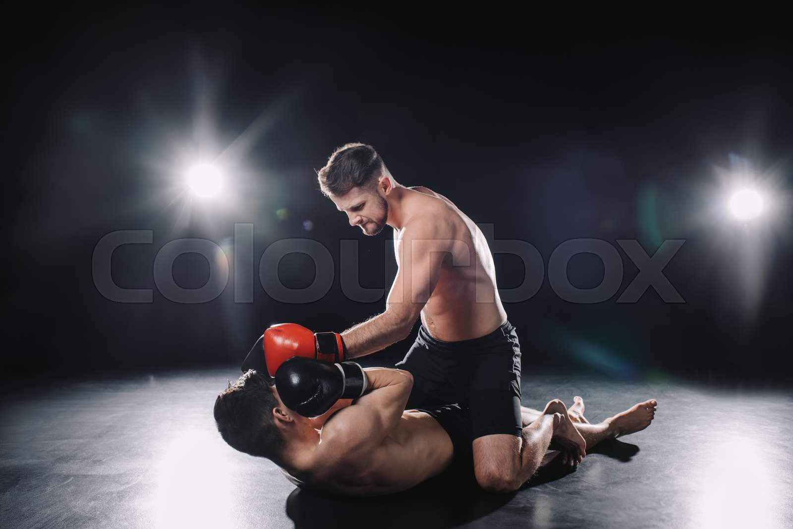 strong mma fighter in boxing gloves sitting on opponent and punching ...