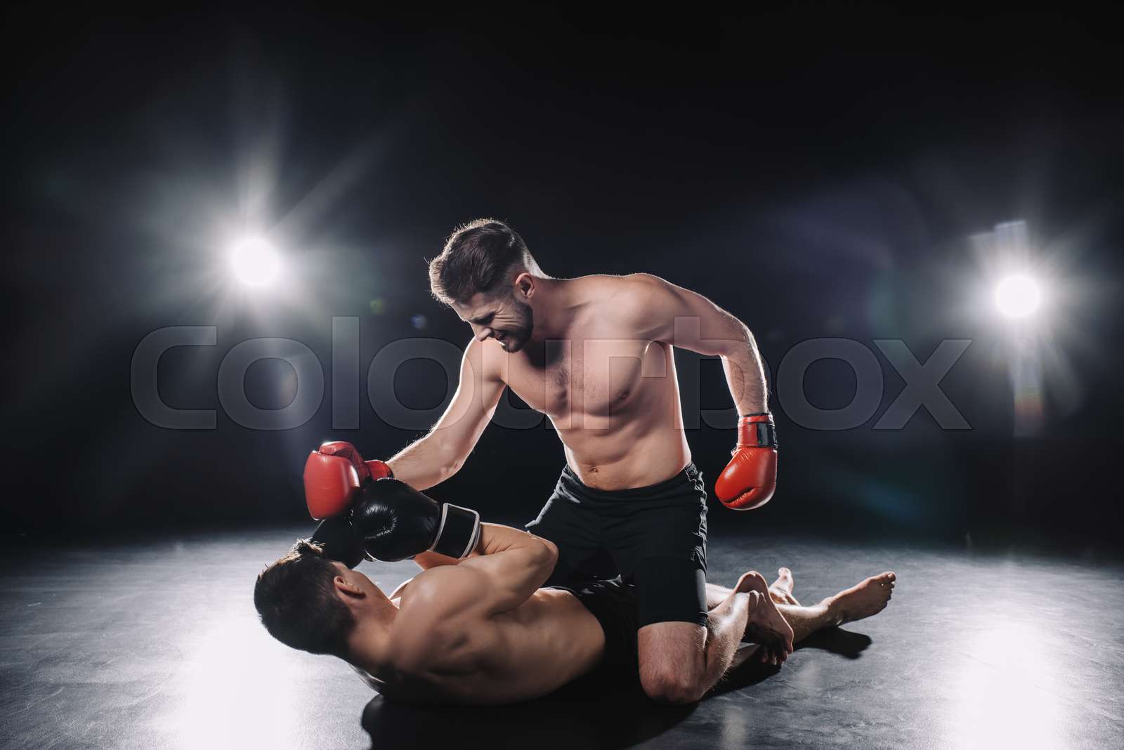 strong mma fighter in boxing gloves punching opponent while sportsman lying on floor | Stock ...