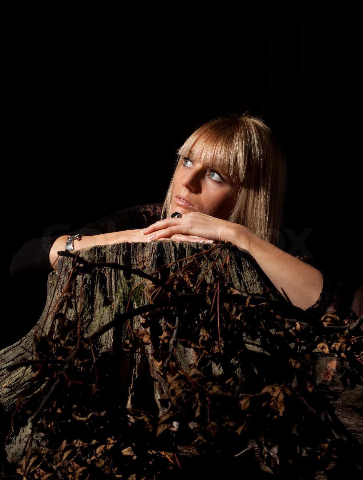 sød ensom pige poserer på stub i et mørkt rum | Stock foto | Colourbox